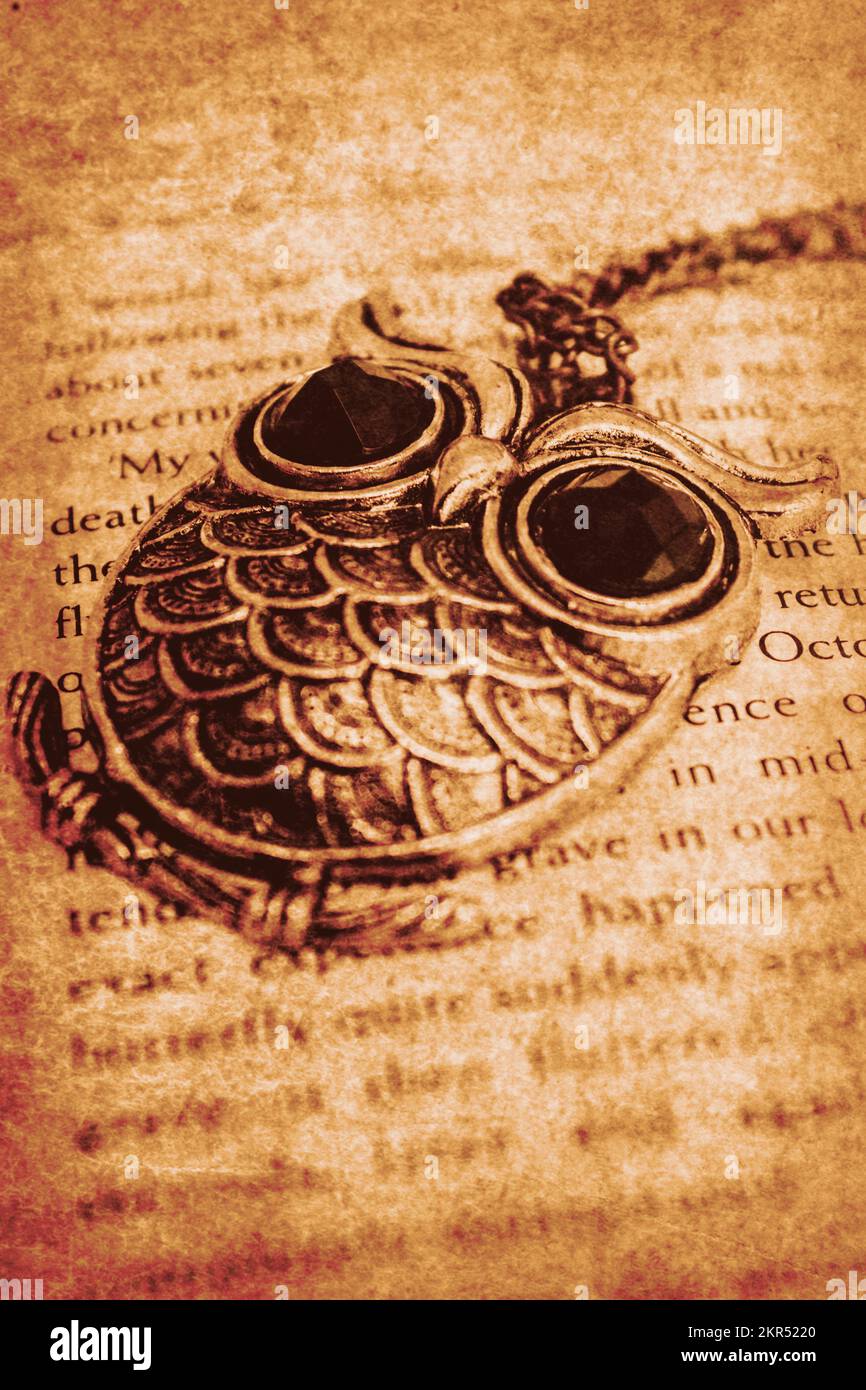 Old-fashioned open textbook with a bird pendant necklace scattered ...