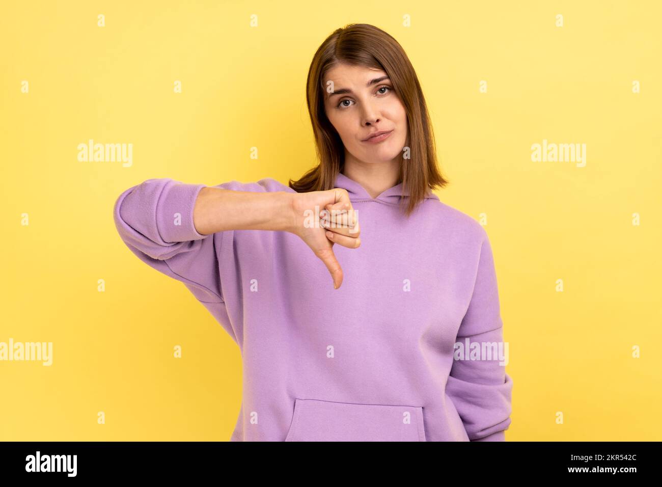 Portrait of upset dissatisfied woman standing with thumb down, negative ...