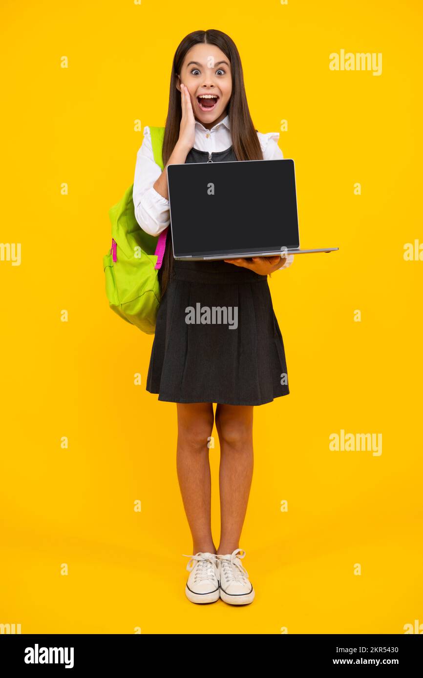 Teen schoolgirl hold laptop on isolated studio background. Cchool ...