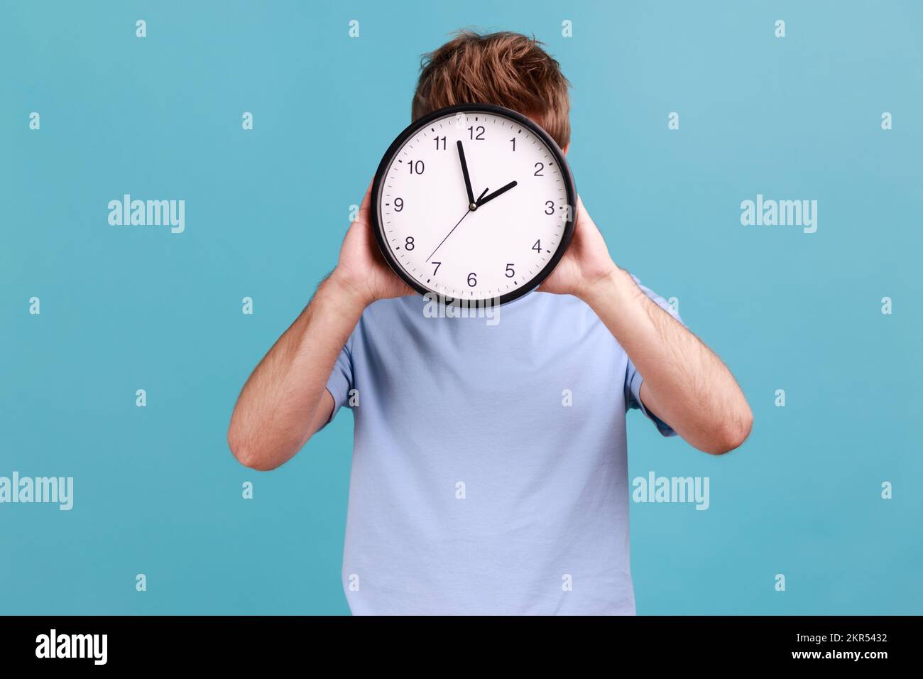 Portrait of unknown anonymous man holding big wall clock hiding his ...