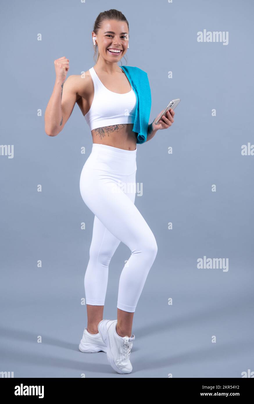 Sporty strong cheerful young woman posing on gray isolated background ...