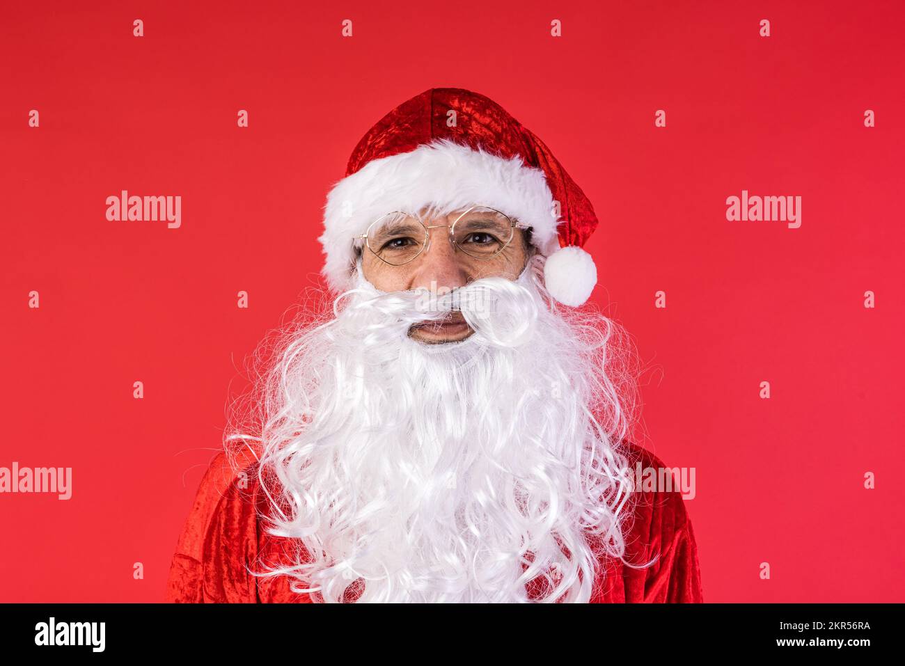 Portrait of a man dressed as Santa Claus, on red background. Christmas ...