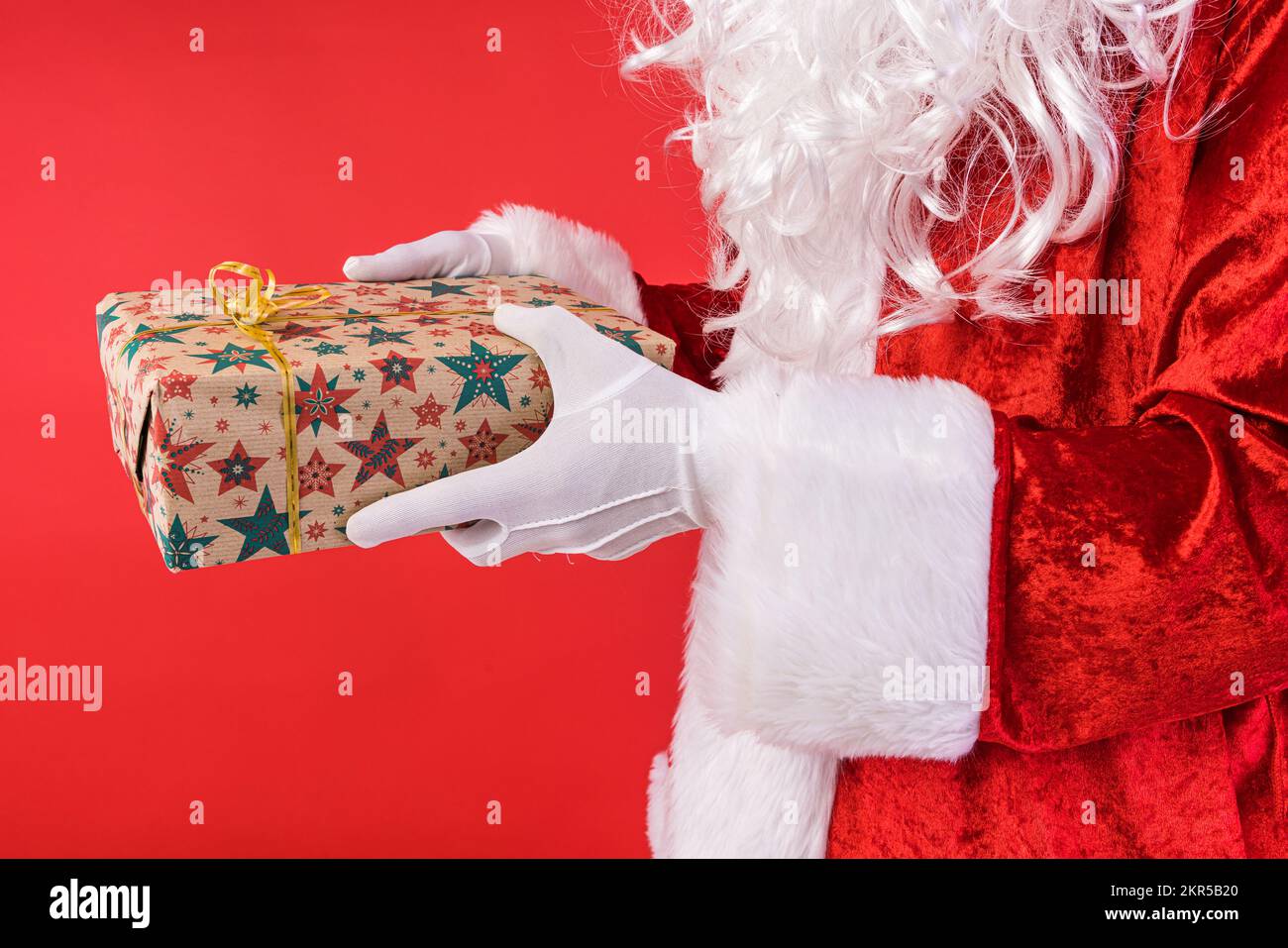 Detail of the hands of a man dressed as Santa Claus with gloves holding ...