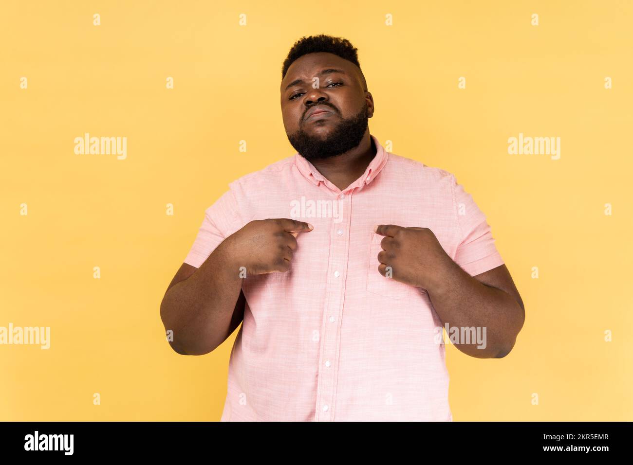 This is me. Portrait of bearded man wearing pink shirt pointing at his ...