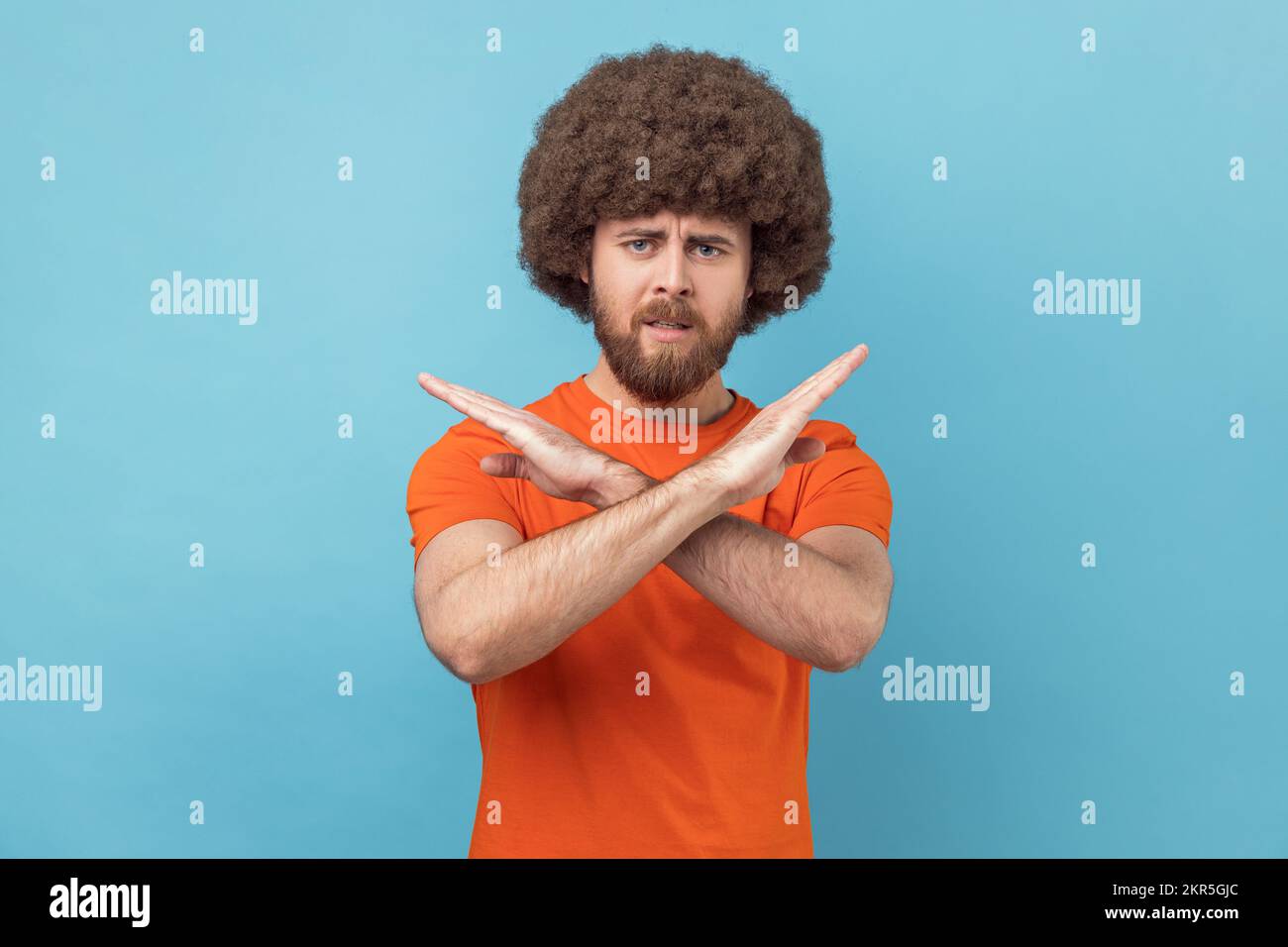 Portrait of man with Afro hairstyle wearing orange T-shirt showing ...