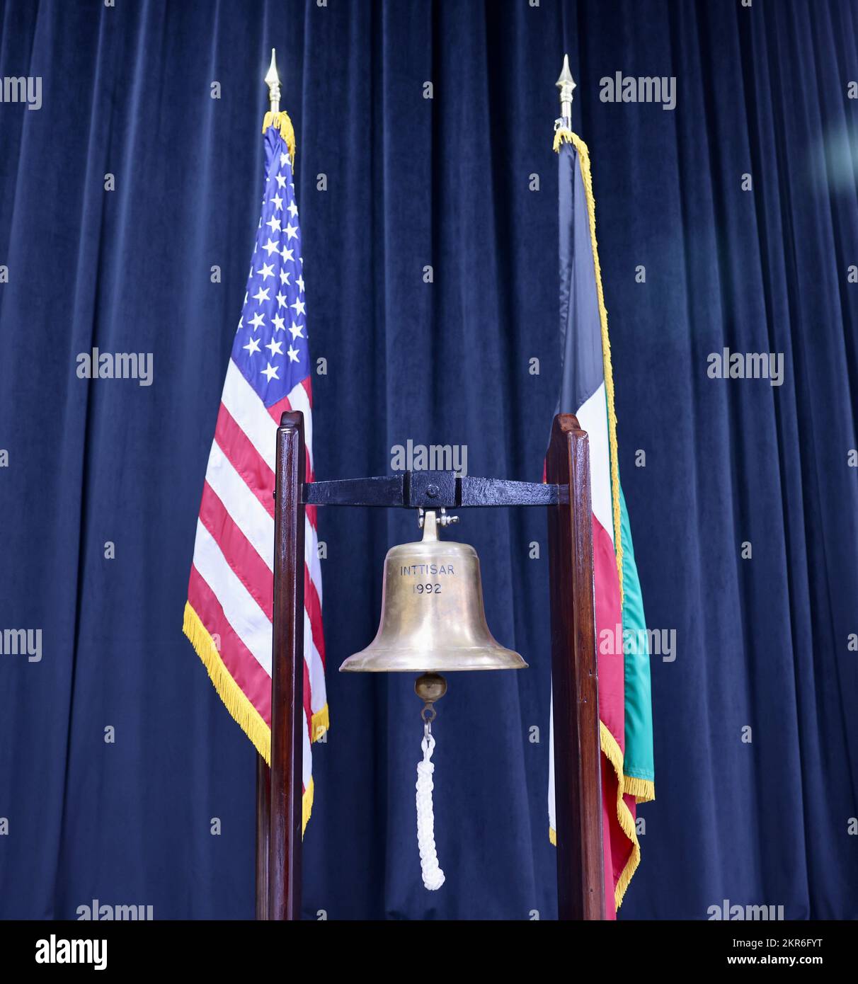 The United States and Kuwait flags, flank a Kuwait Navy bell from the ...