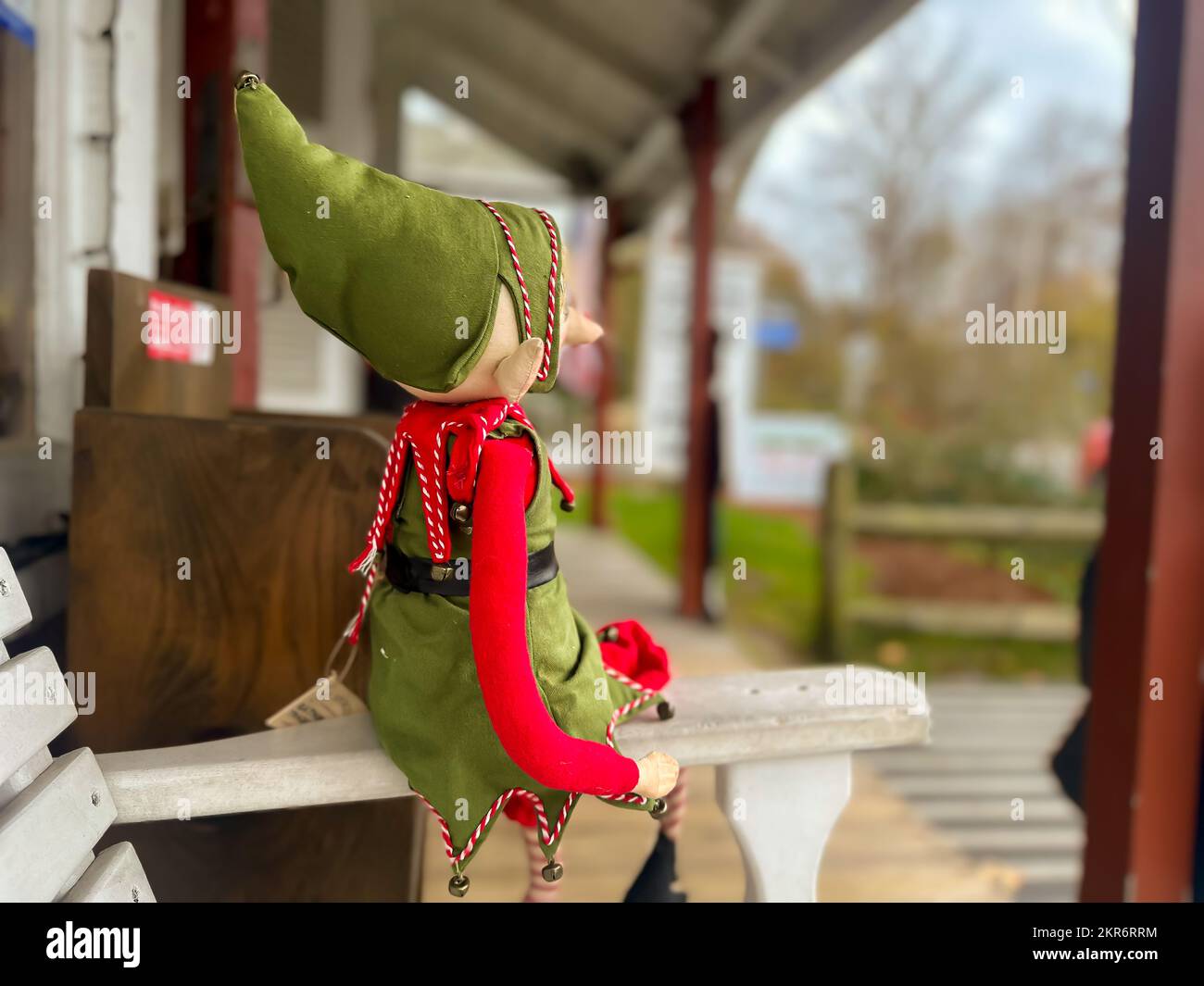 Photo of a holiday Elf sitting on the arm of an outside bench Stock ...