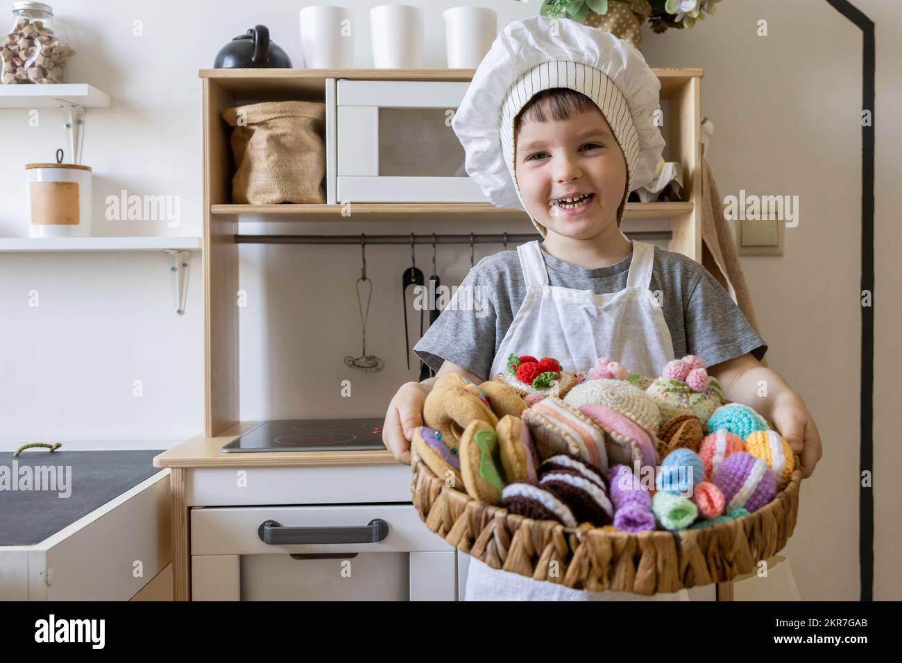 Cute little baby boy in chef hat and apron playing at childish kitchen ...