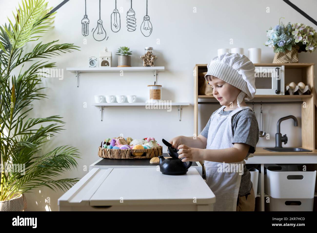 Cute little baby boy in chef hat and apron playing at childish kitchen ...