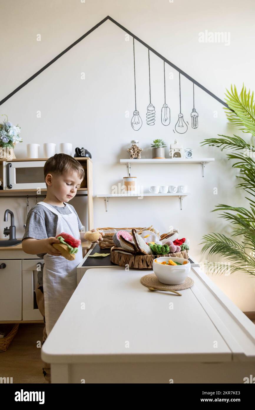 Cute little baby boy in chef hat and apron playing at childish kitchen ...