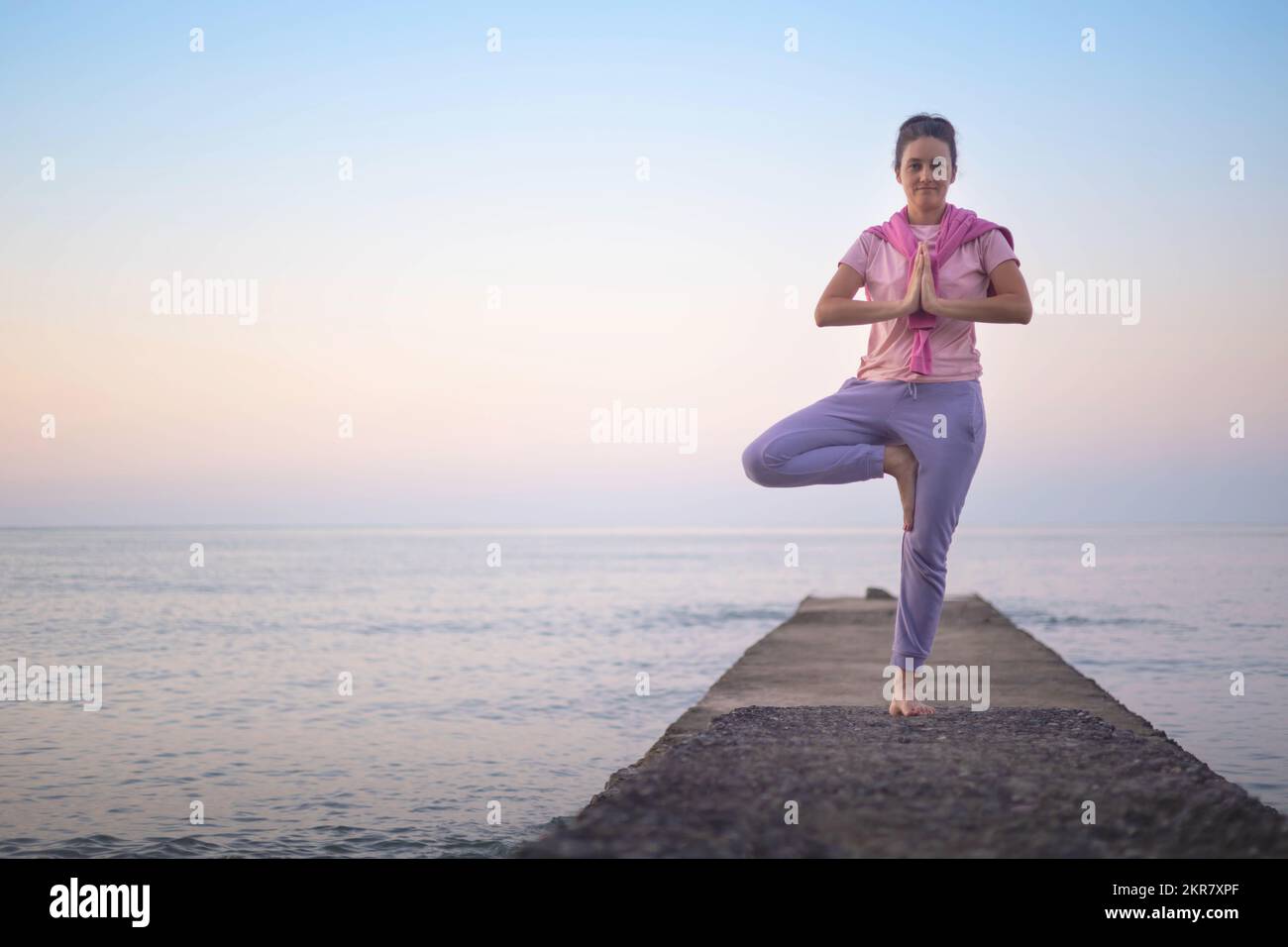 Active female practicing yoga vrikshasana tree pose hands namaste at ...