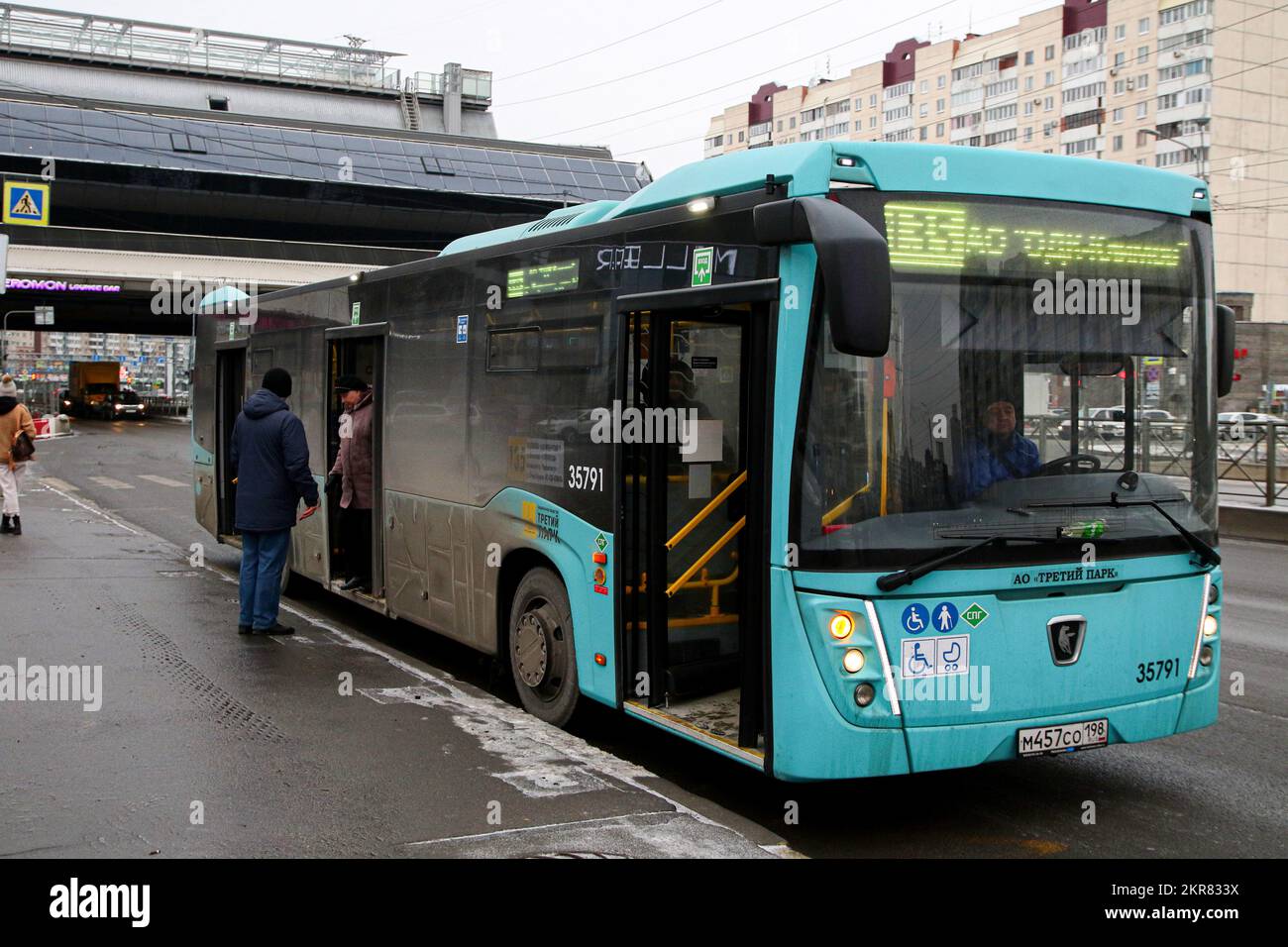 Passengers board a blue passenger bus at a public transport stop on ...