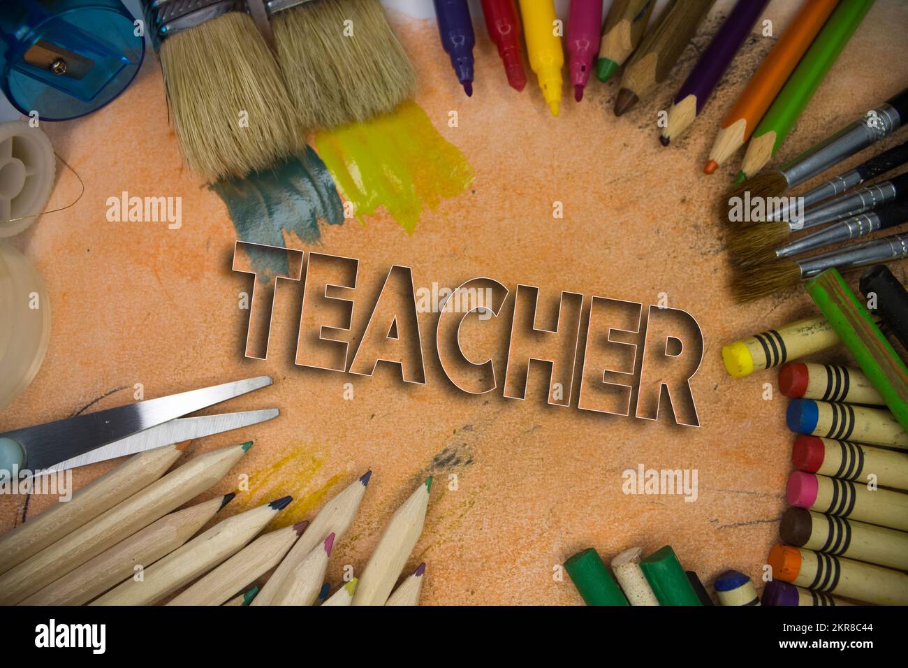 Overhead shot of school supplies with Teacher text. Brushes, pencils ...