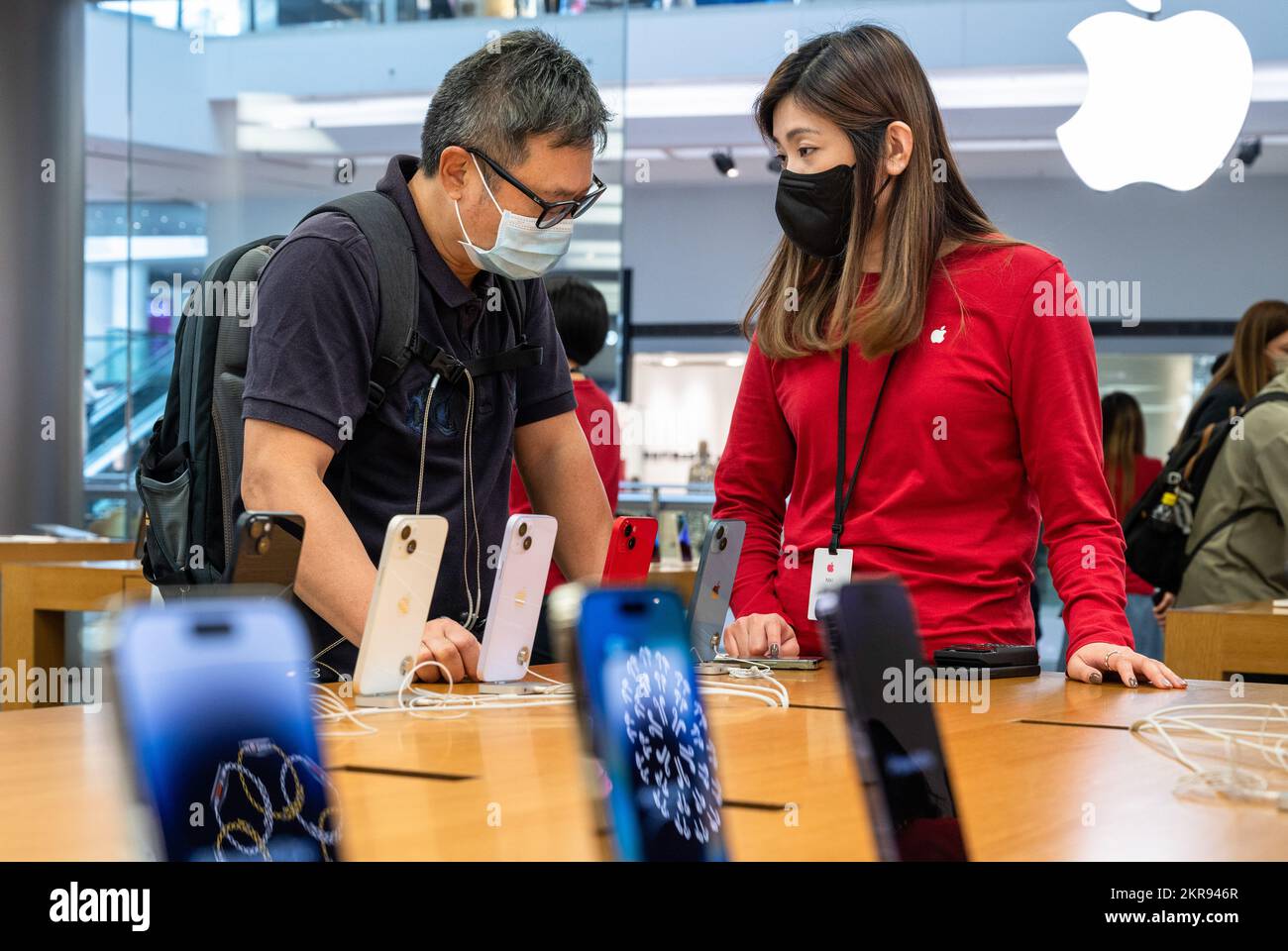 An employee assists a customer with purchasing an Apple iPhone 14 at ...