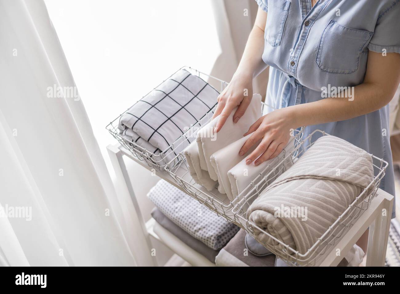 Modern housewife putting neatly folded towels, pillowcases, duvet ...