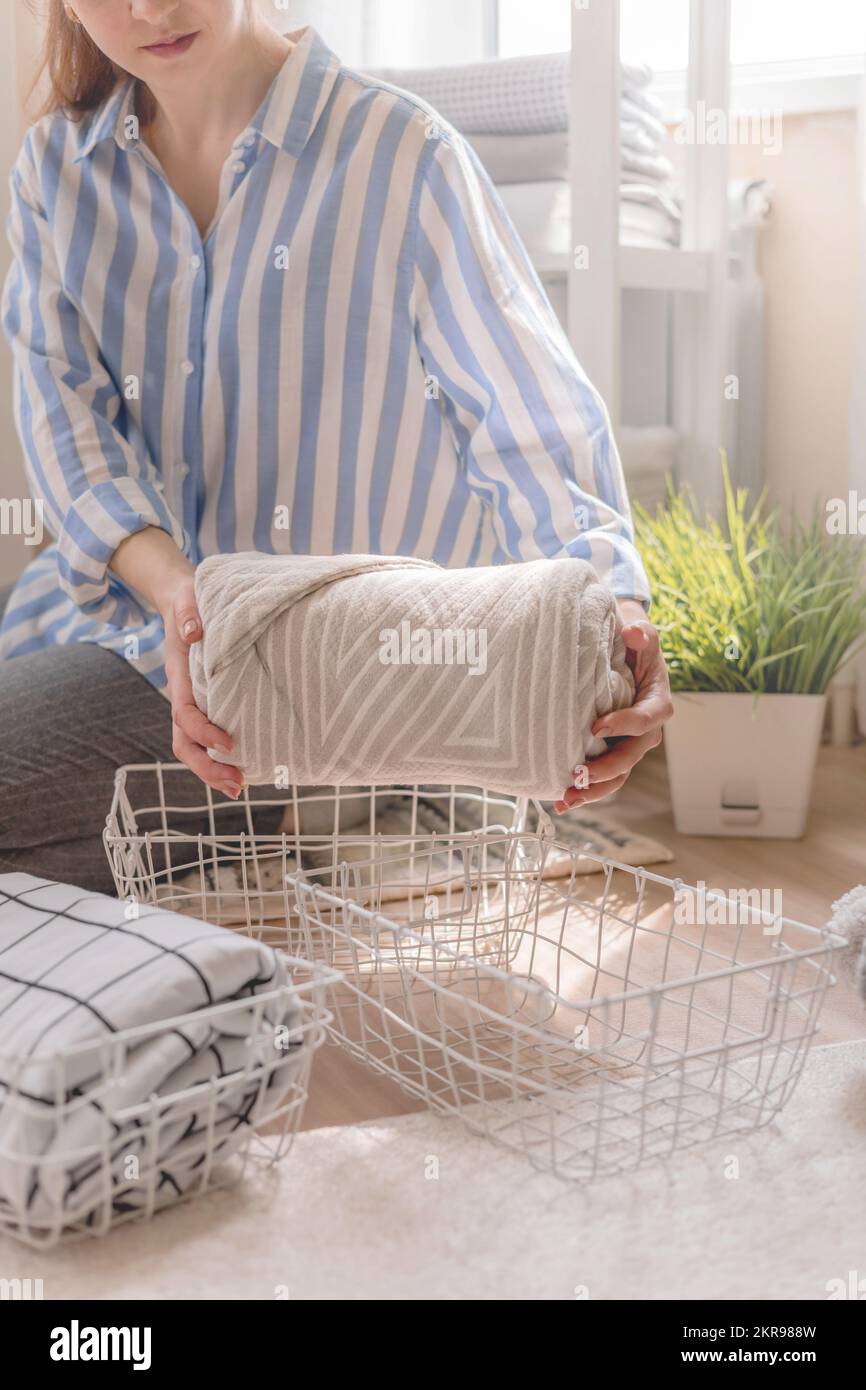Modern housewife putting neatly folded towels, pillowcases, duvet ...