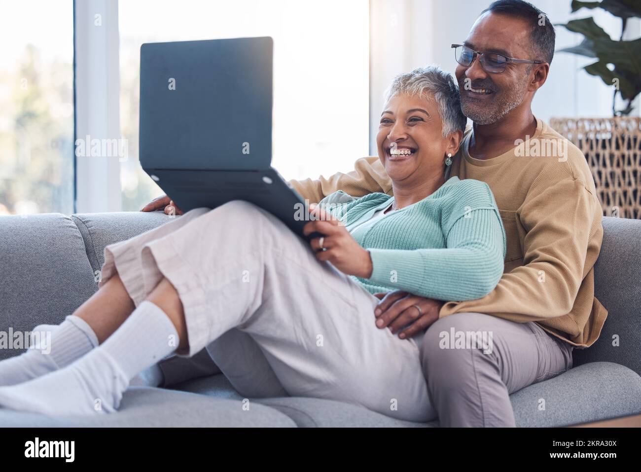 Mature couple, laptop and relax on sofa in living room, house and home ...