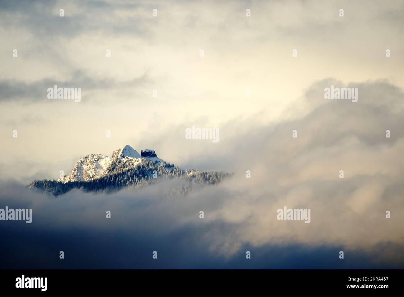 Mountain peak covered in snow sticking out of the clouds - winter ...