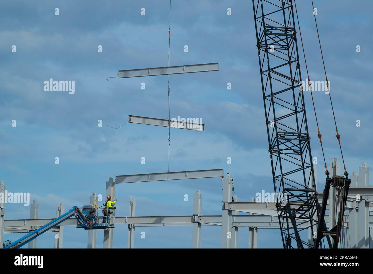 Construction workers weld steel beams to the second wing of the new ...