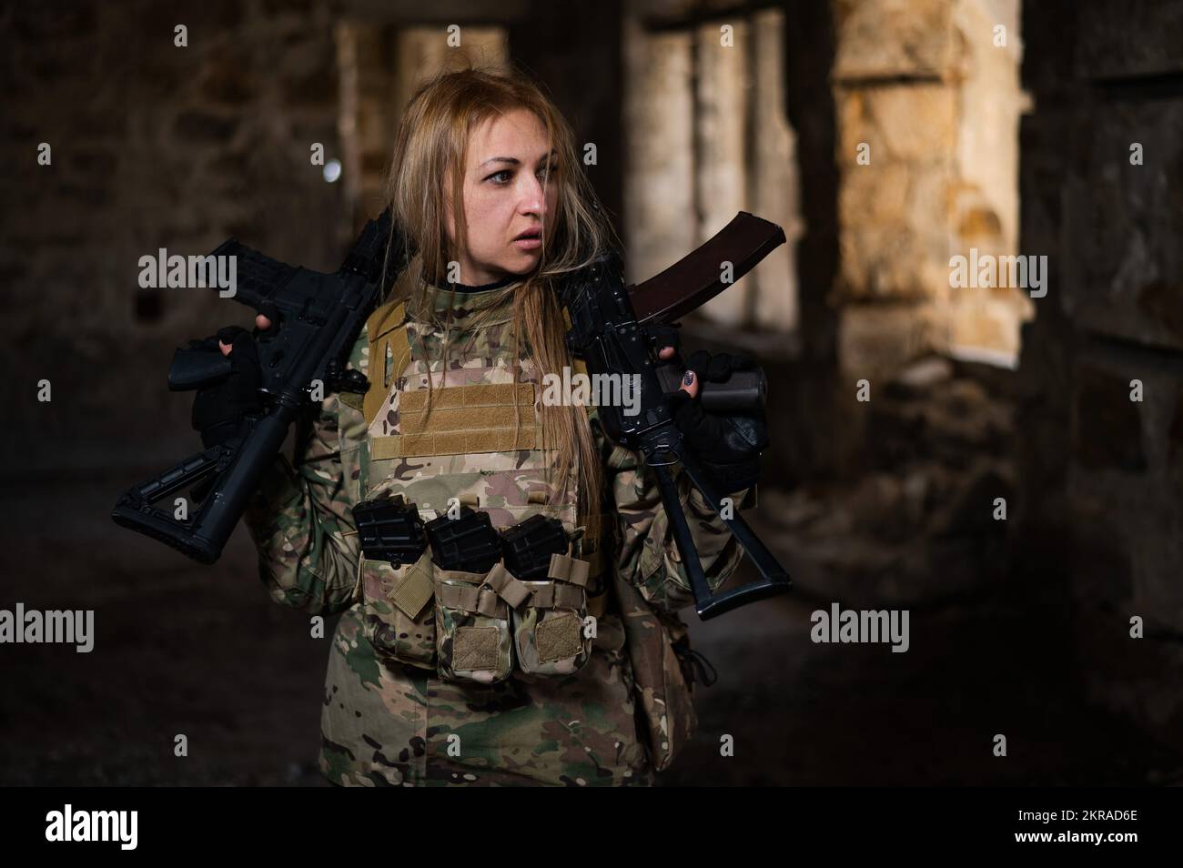 Blonde woman in army uniform holding a firearm in an abandoned building ...