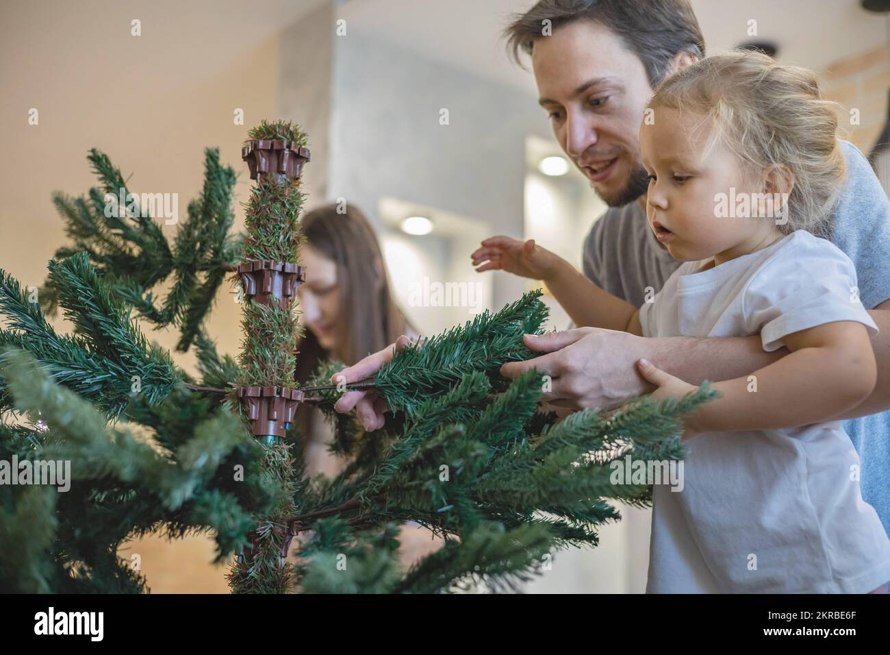 Family assembling, shaping hook-in artificial Christmas Tree at home ...