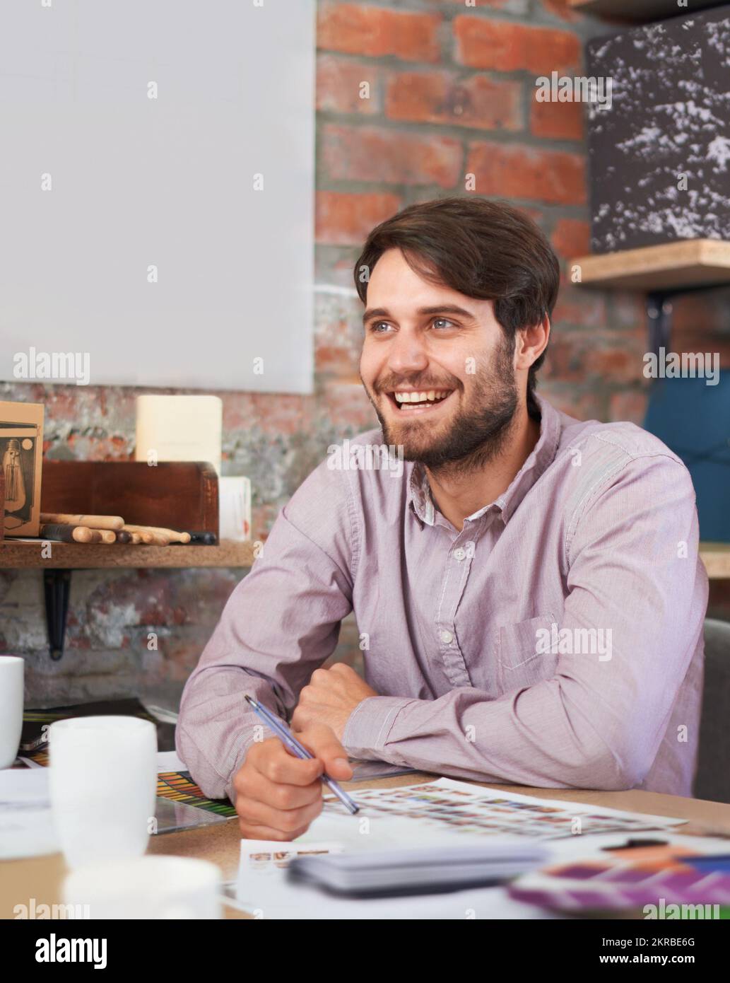 Feeling inspired. A handsome young designer smiling as he works in his ...