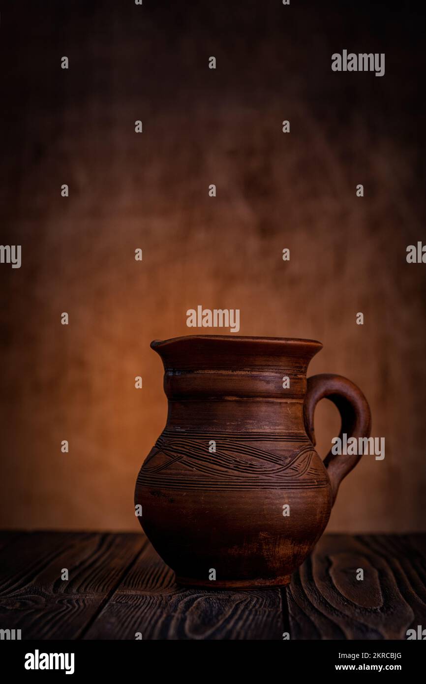 Clay jug on a dark background on a wooden table Stock Photo - Alamy