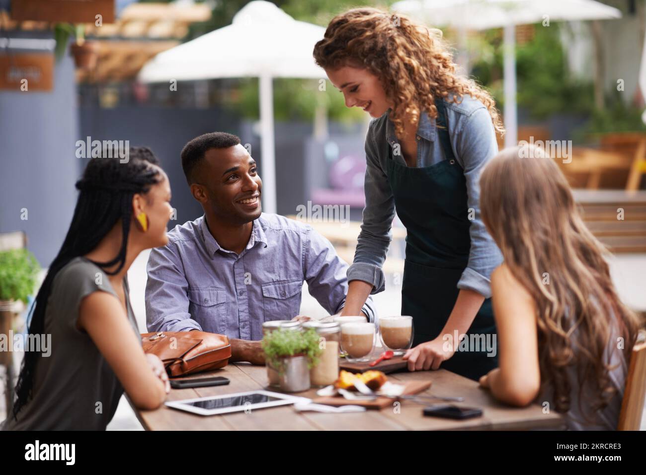 Would you like anything else. a waitress serving her customers at a ...