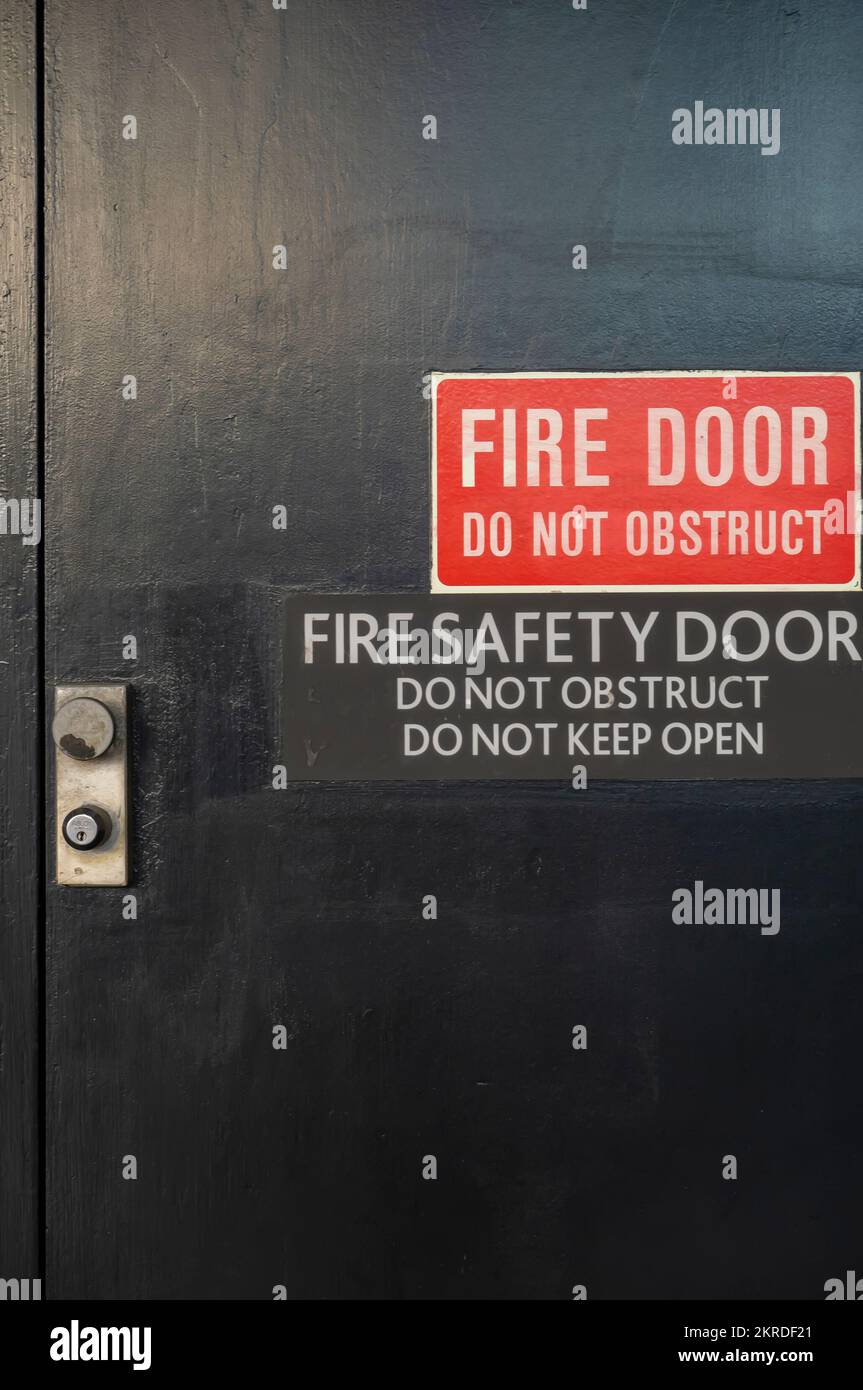 A black fire door with red and white warning signage Stock Photo - Alamy