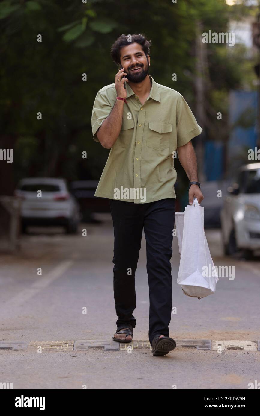 Young man talking on mobile phone while walking on street Stock Photo ...