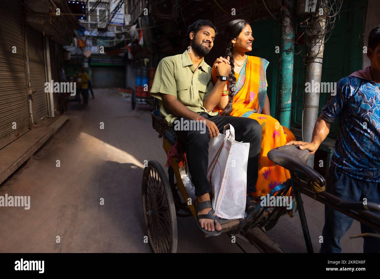 Happy young couple riding rickshaw with holding their hands together ...