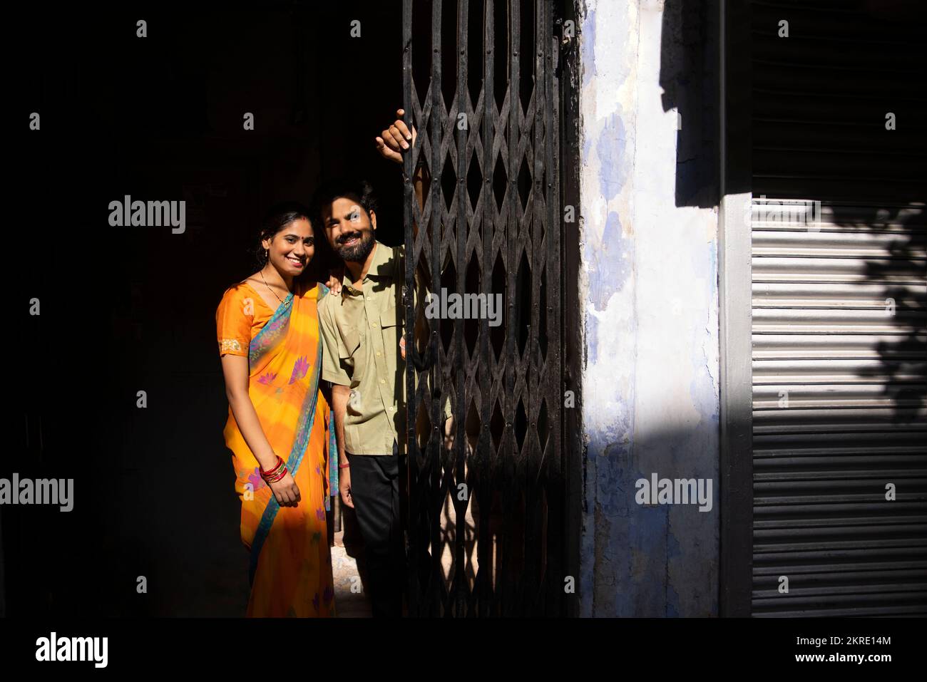 Happy couple standing together by collapsible gate Stock Photo - Alamy