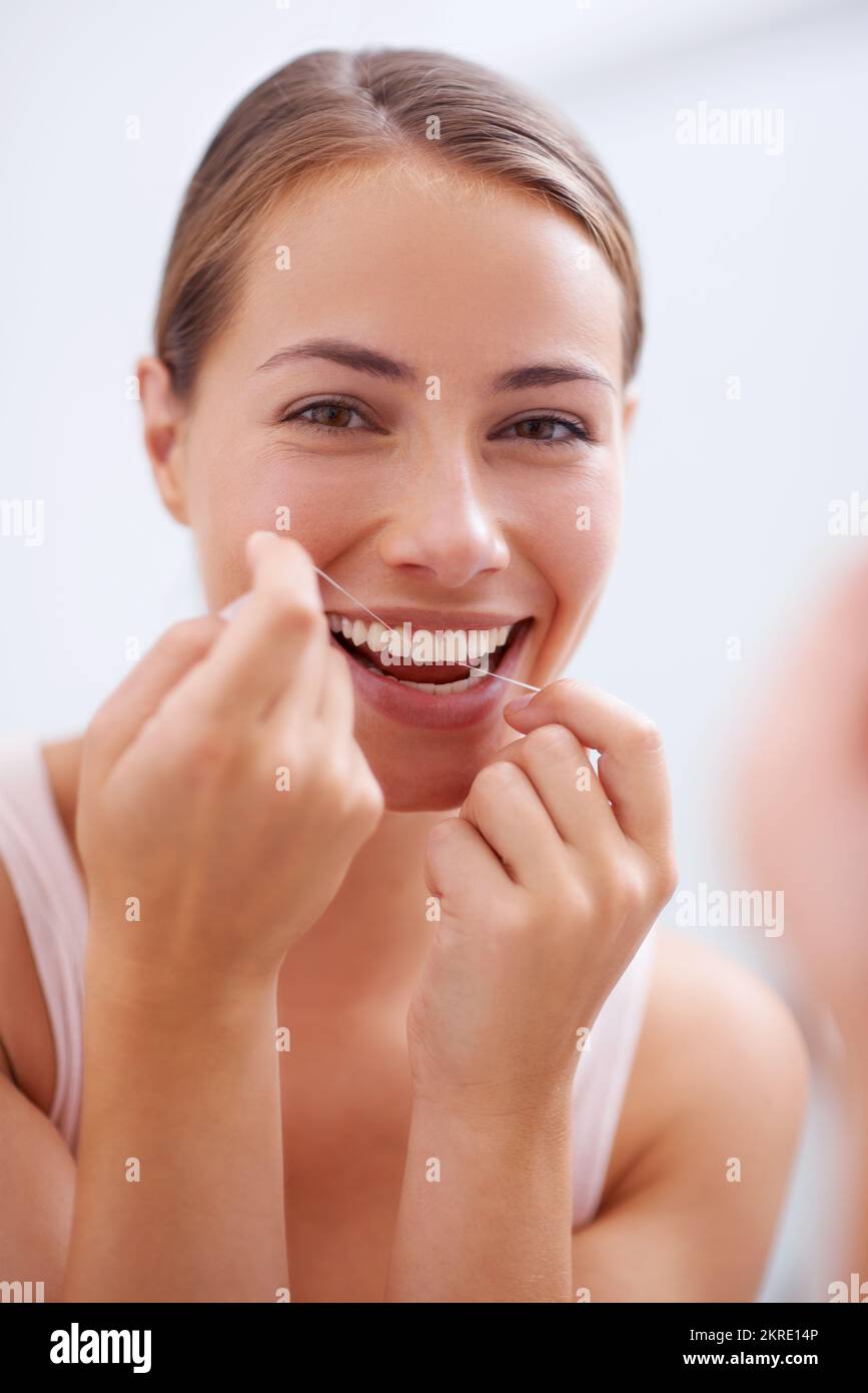 Dental hygiene is a priority. A young woman flossing her teeth Stock ...