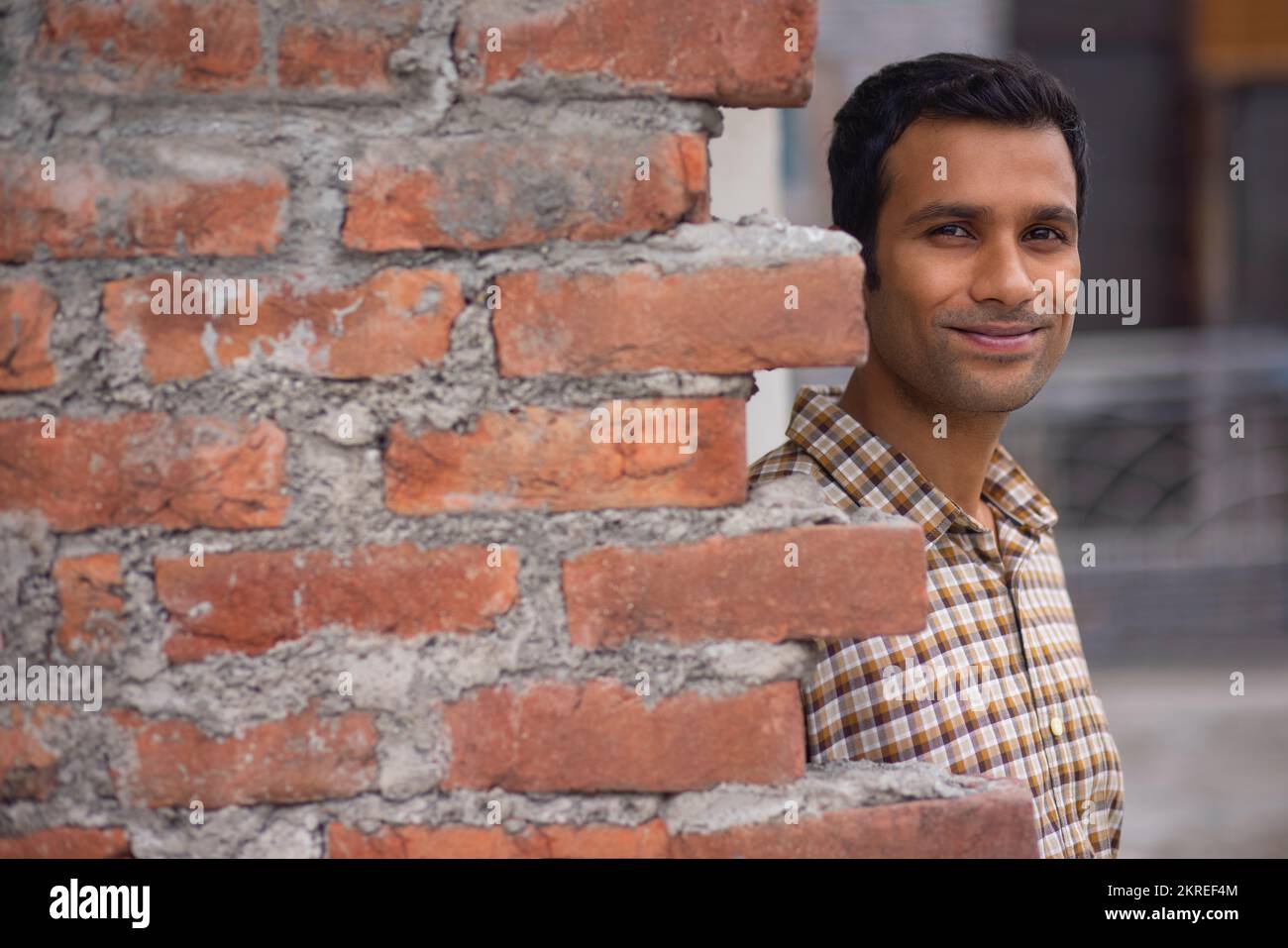 Portrait of young man standing behind brick wall Stock Photo - Alamy