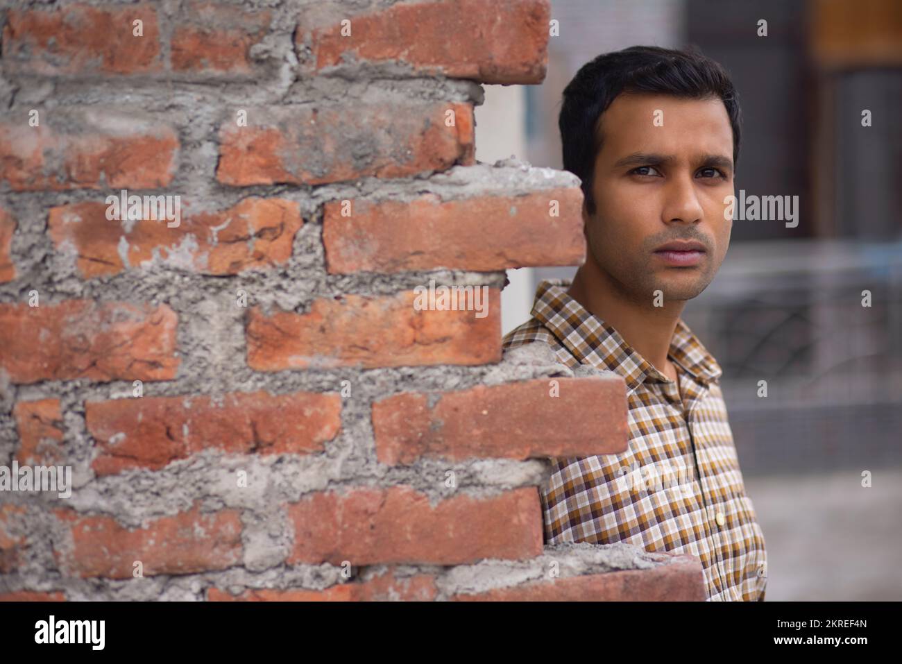 Portrait of young man standing behind brick wall Stock Photo - Alamy