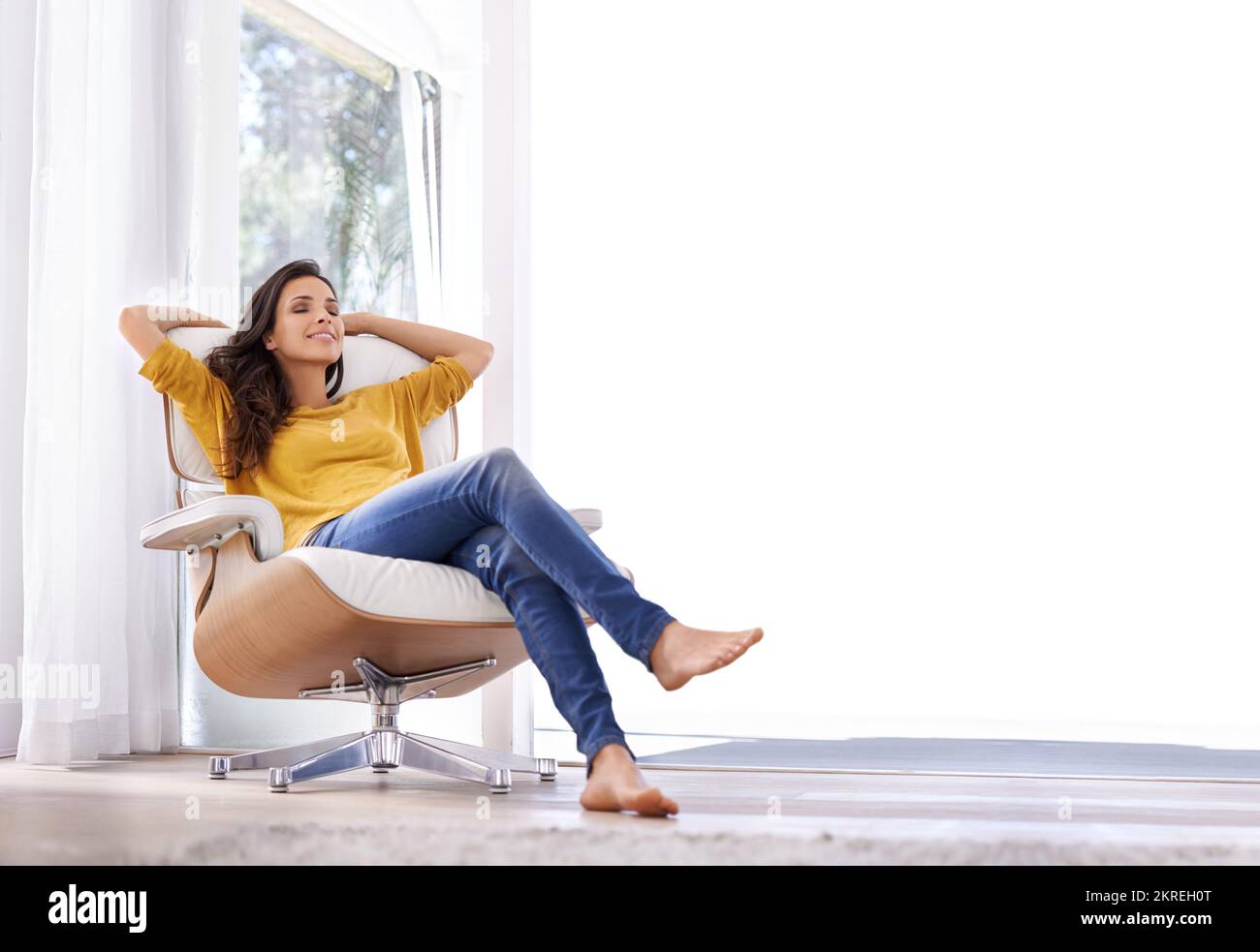 Taking it easy. A woman relaxing on a chair with her hands behind her ...