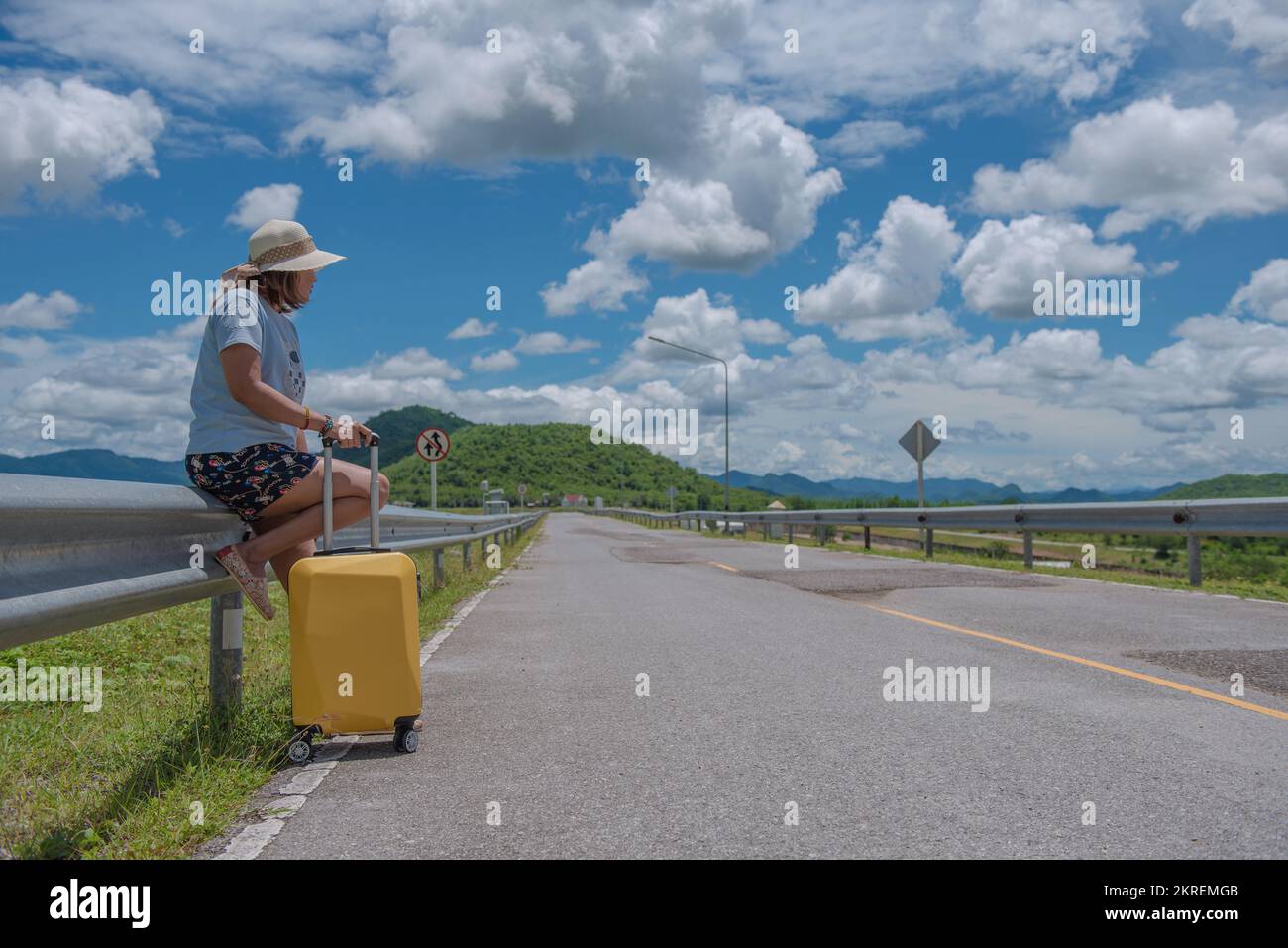 Hitchhike Asian woman on a road with traveling suitcase waiting for a ...