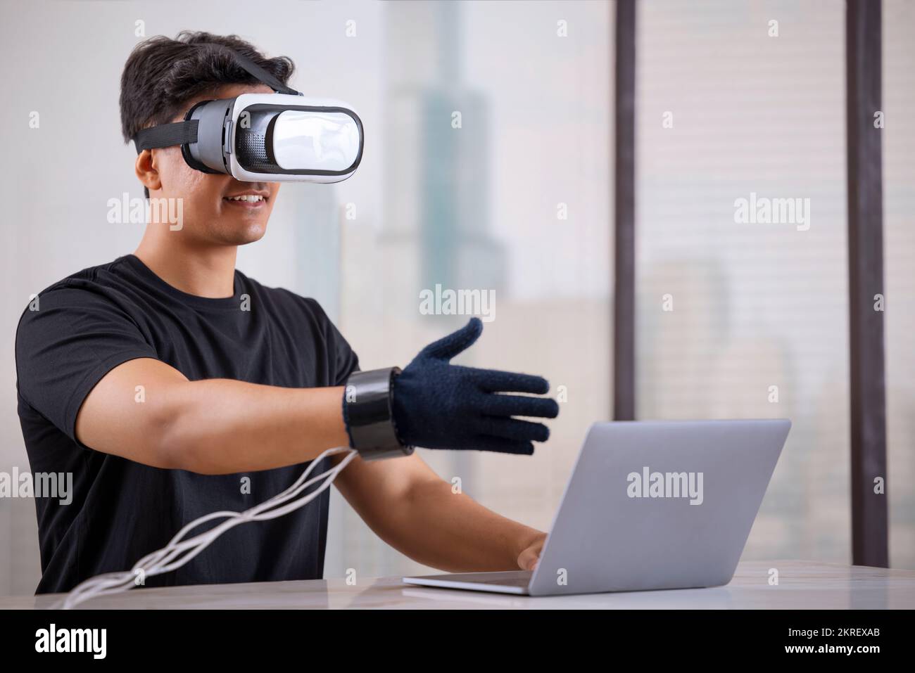 Man wearing VR headset and haptic glove interacting with virtual object ...
