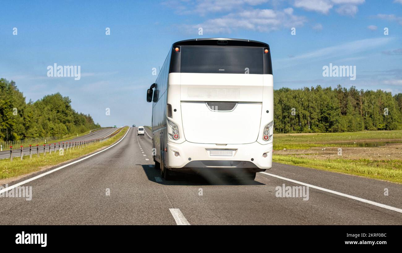 New modern passenger bus on the road in summer against the blue sky ...
