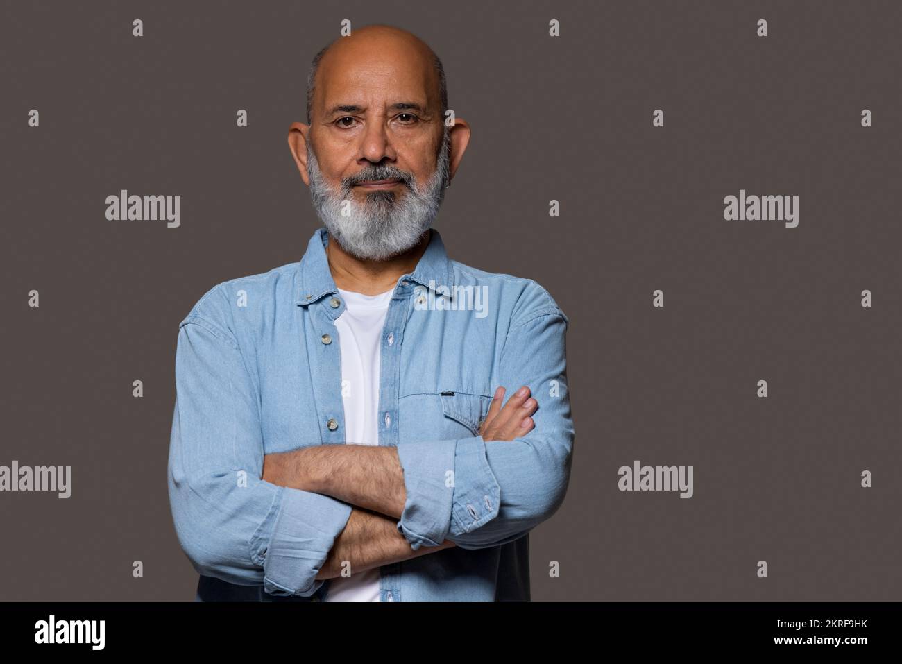 Portrait of senior man with arm crossed against grey background Stock ...
