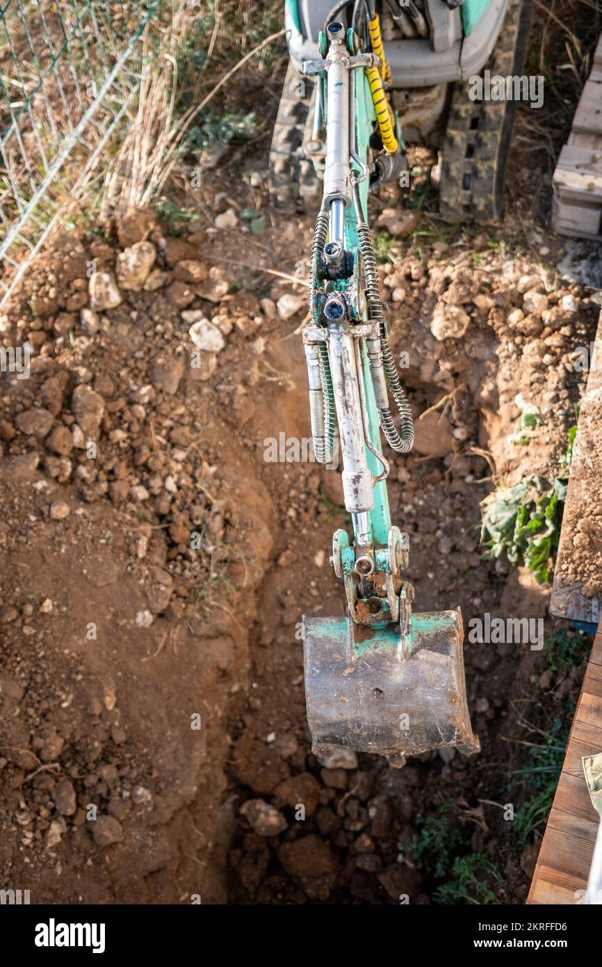 Mini excavator digs a trench to lay pipes. Close up of an excavator ...