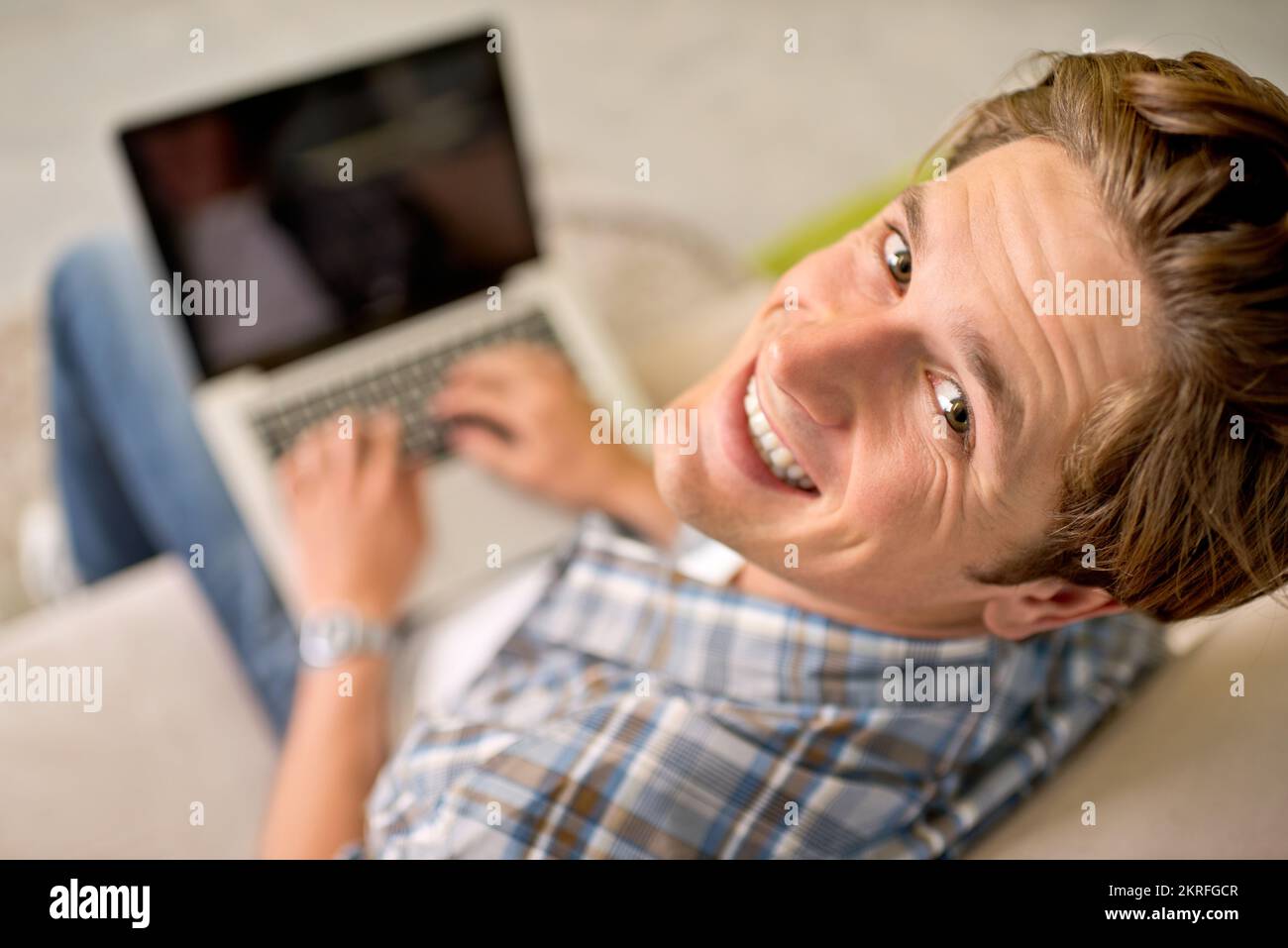 My laptop is great. High angle shot of a handsome young man using his ...