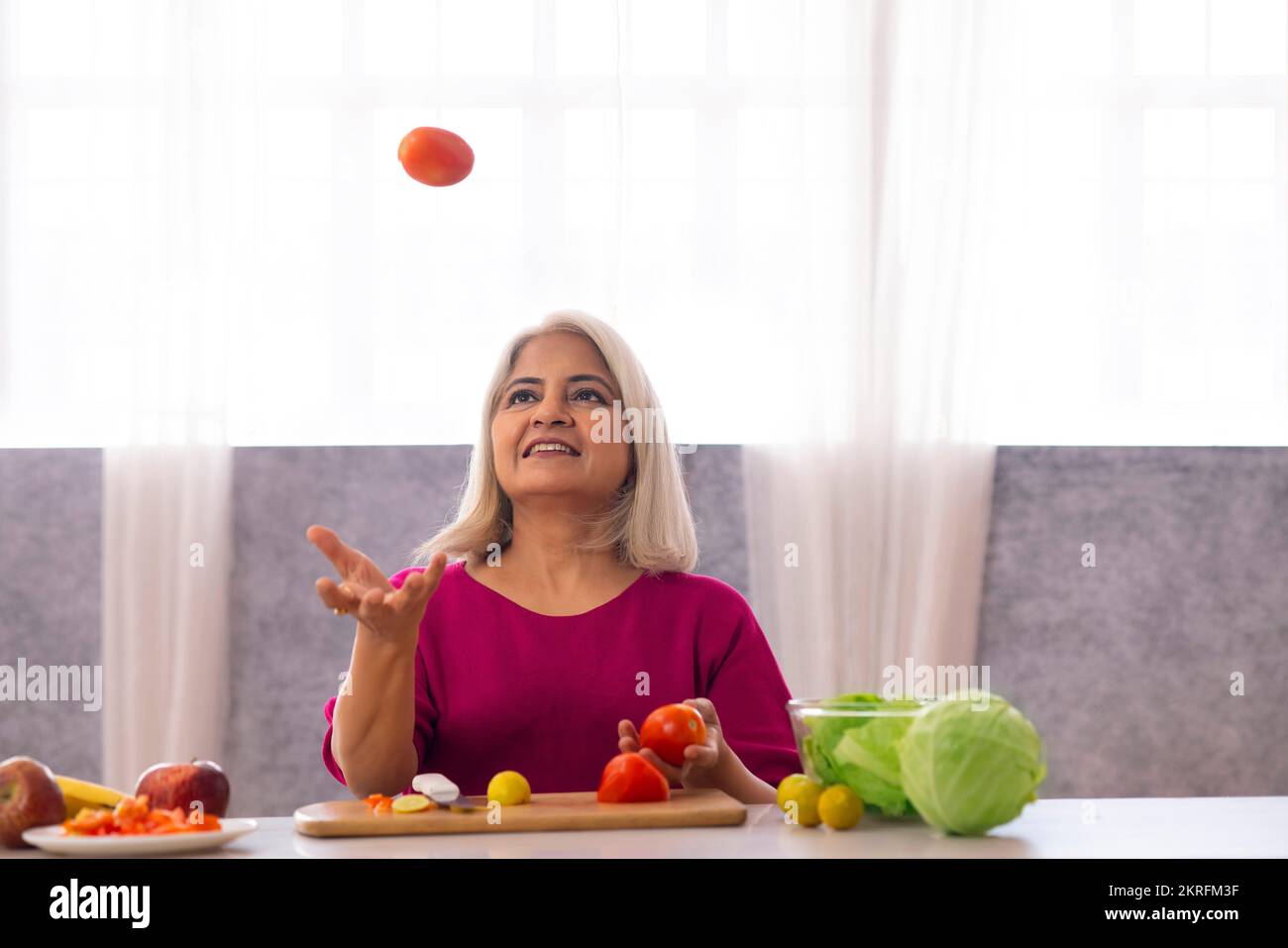 Old woman throwing tomato in the kitchen Stock Photo - Alamy