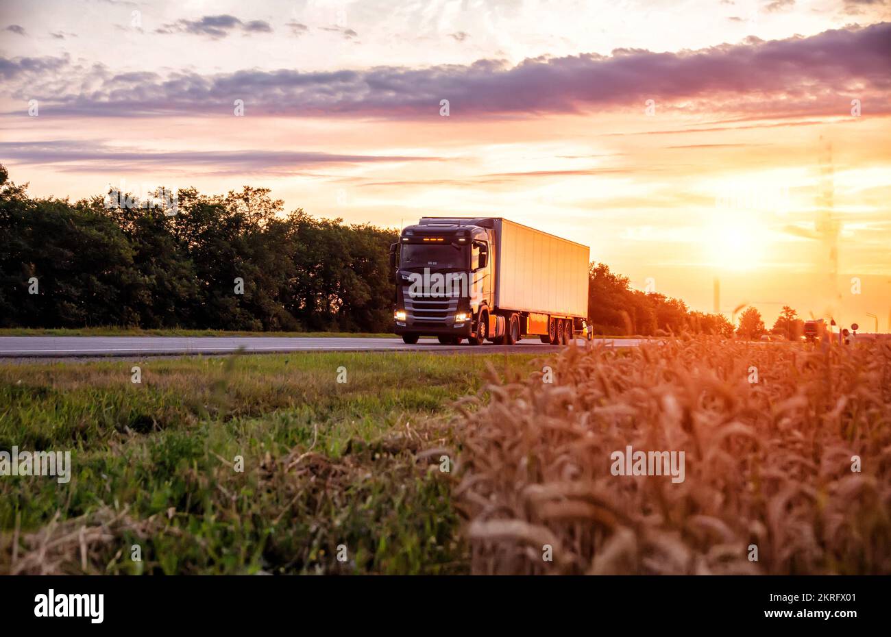 Modern wagon truck transports cargo against the background of sunset ...