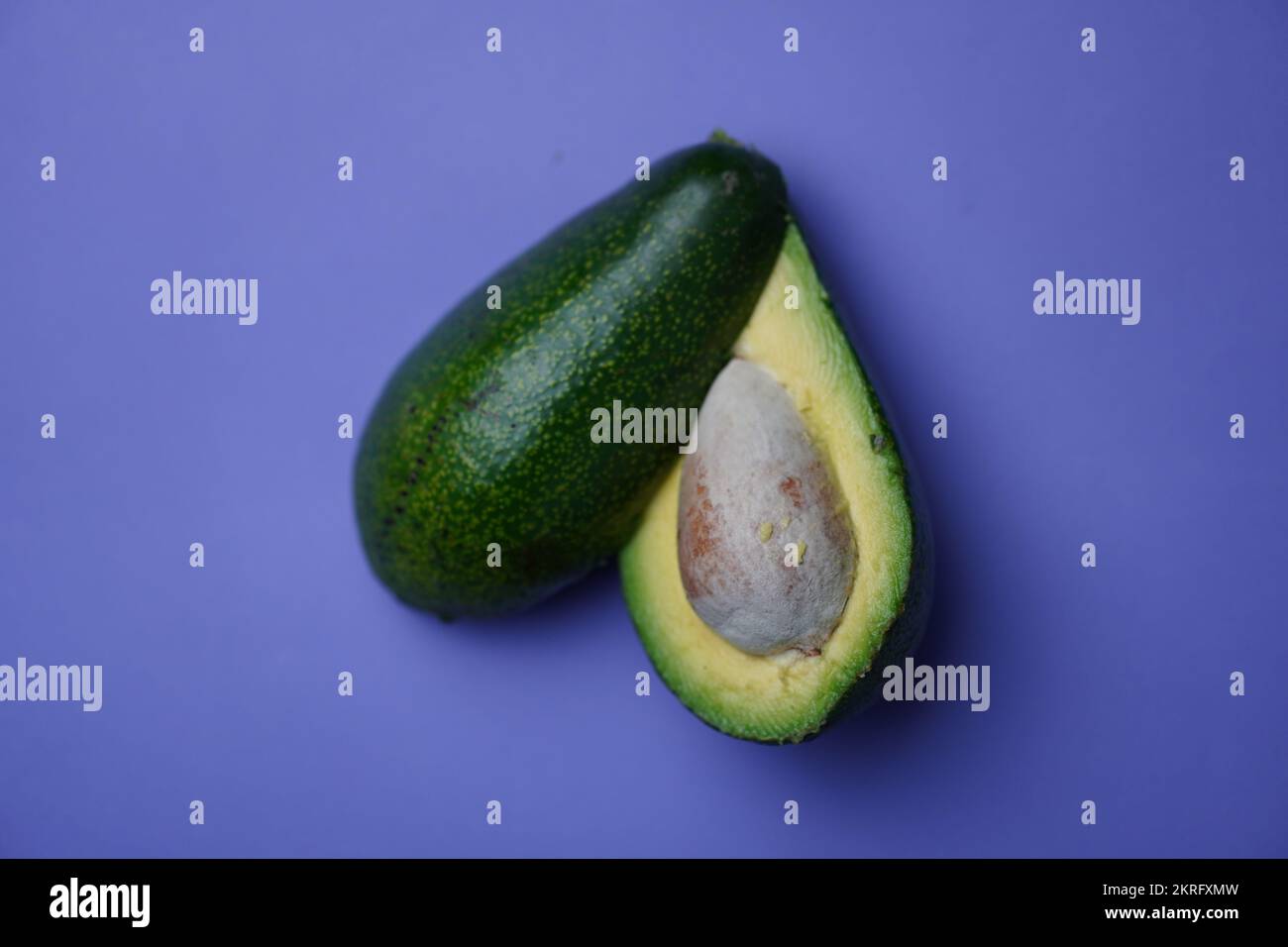 green avocado on purple background Stock Photo - Alamy