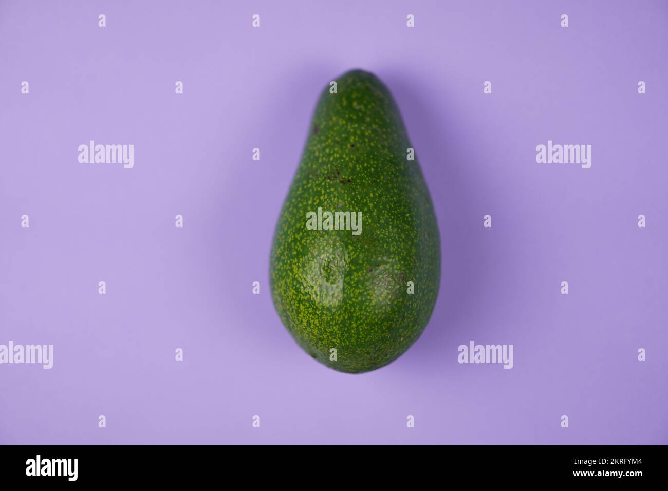 green avocado on purple background Stock Photo - Alamy