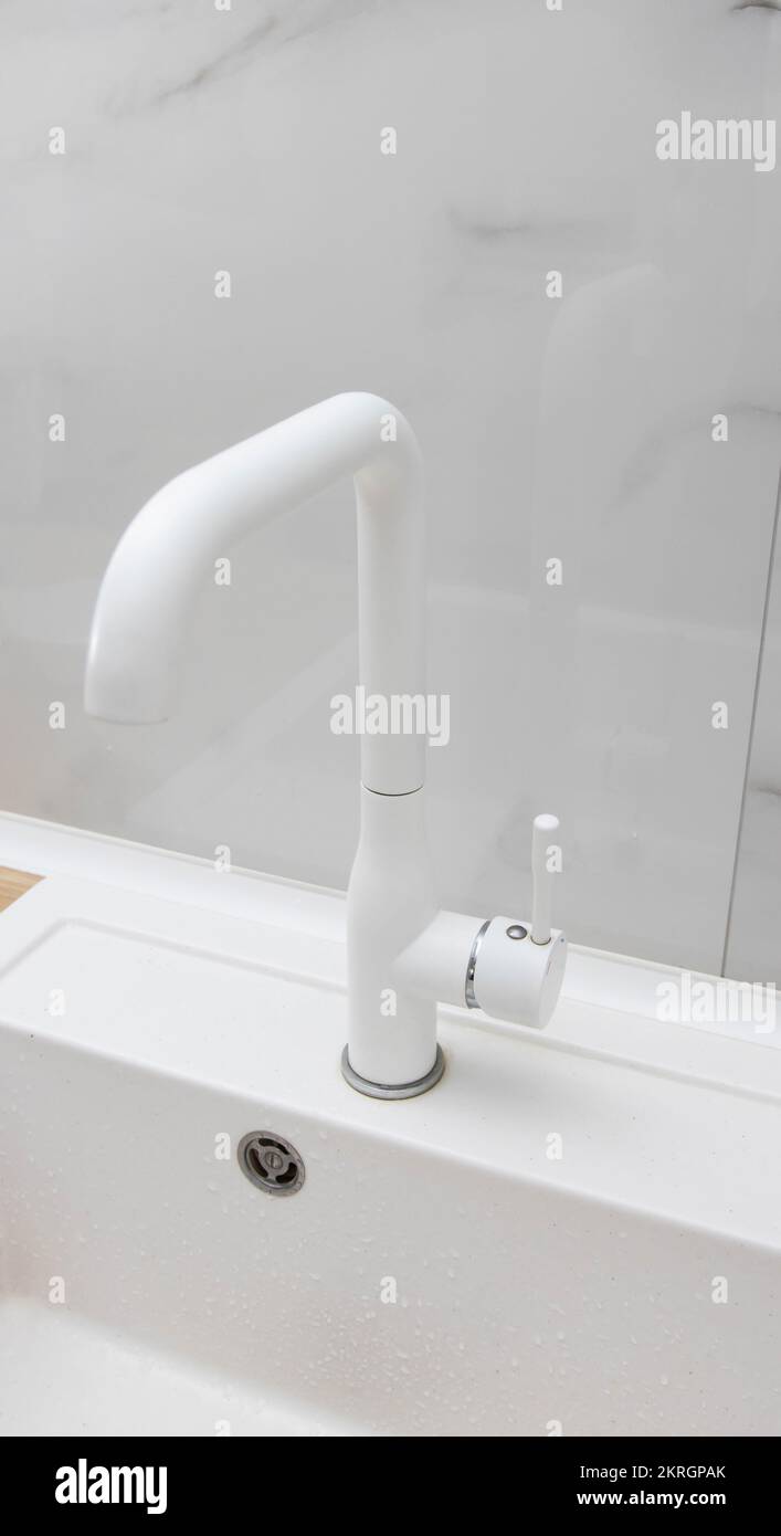 Modern white faucet in the kitchen in the sink against the background ...