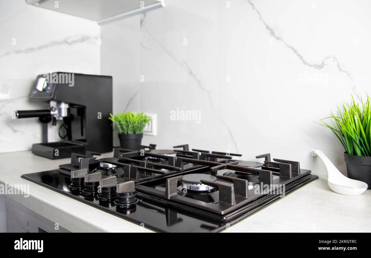 Modern kitchen with gas hob against white granite tiles. Decoration ...