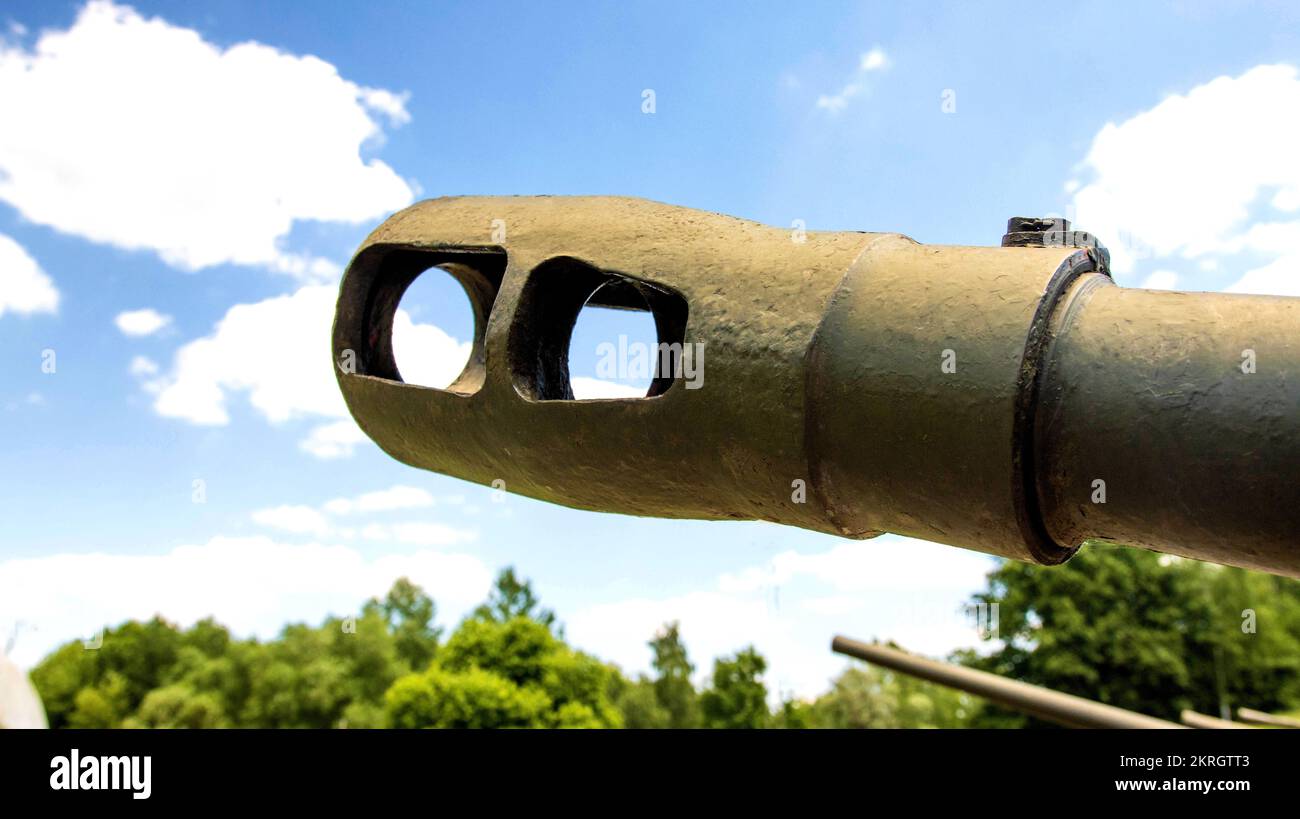 The muzzle of a cannon of a military tank against the blue sky, close ...