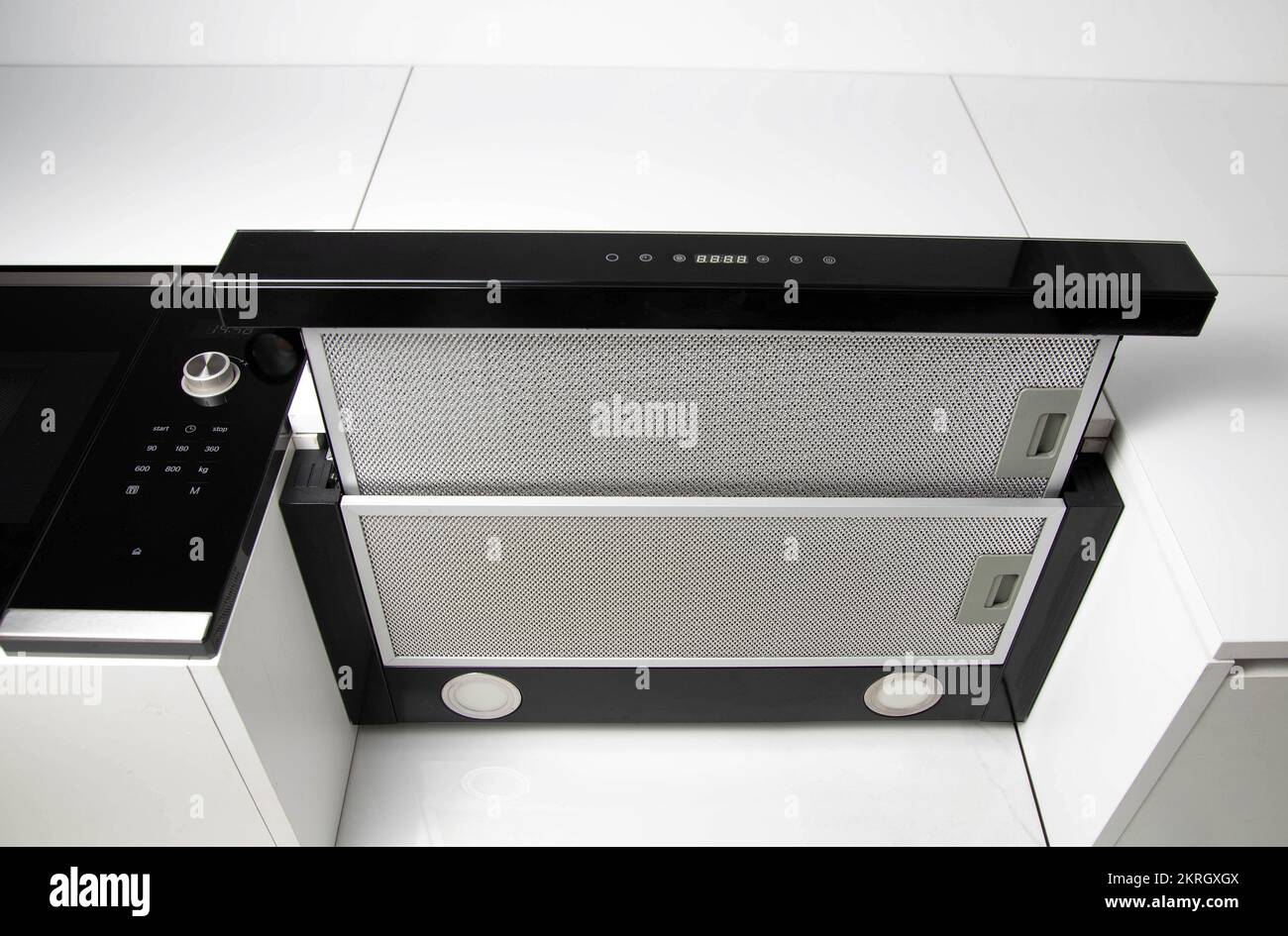 A modern black cooker hood in a white kitchen with a grease and ...